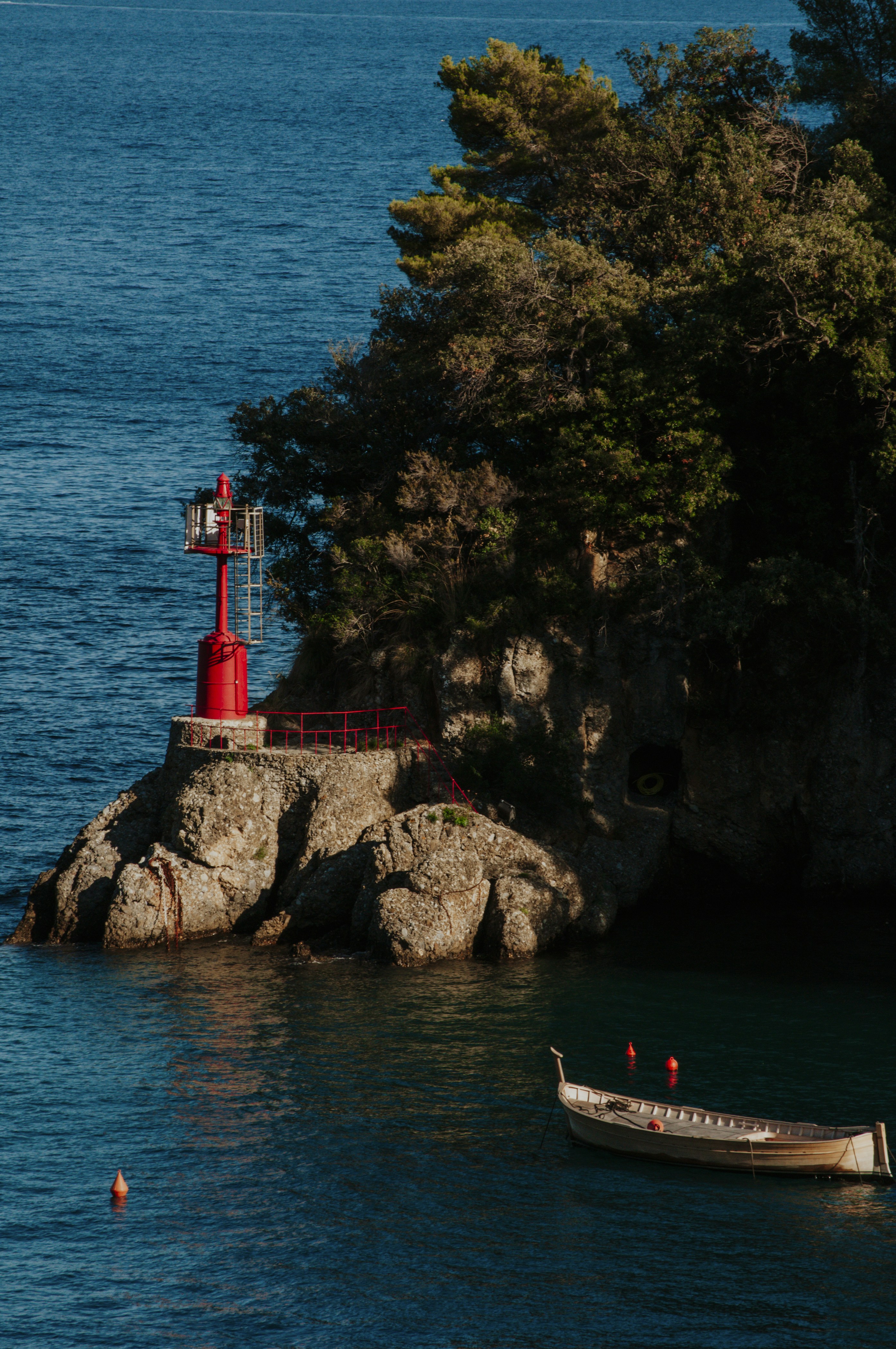 Red beacon over stone outcrop: a lone boat and tranquil blue fjord