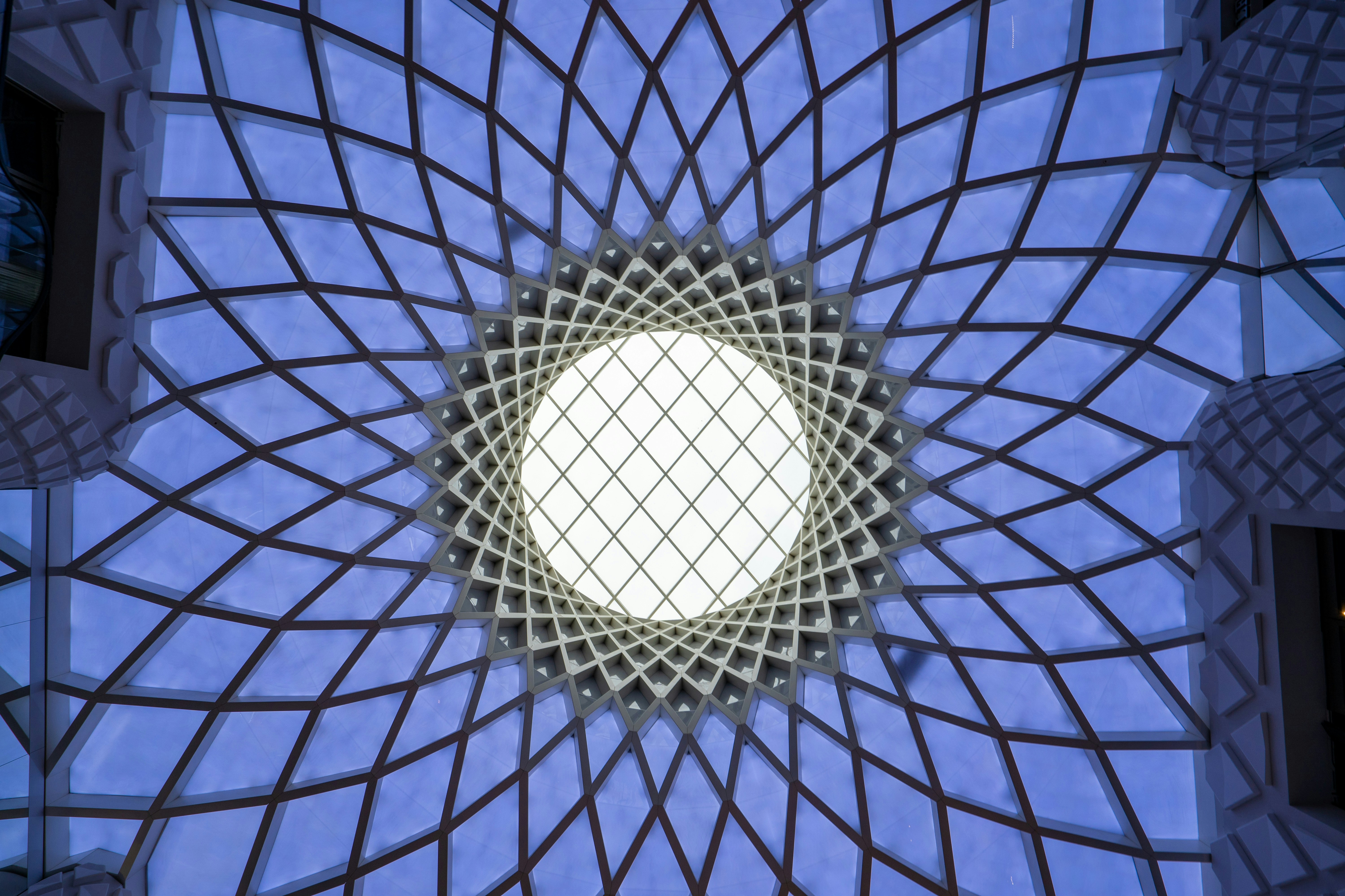 Intricate geometric patterns of a skylight, showcasing a central circular light surrounded by a web-like structure.