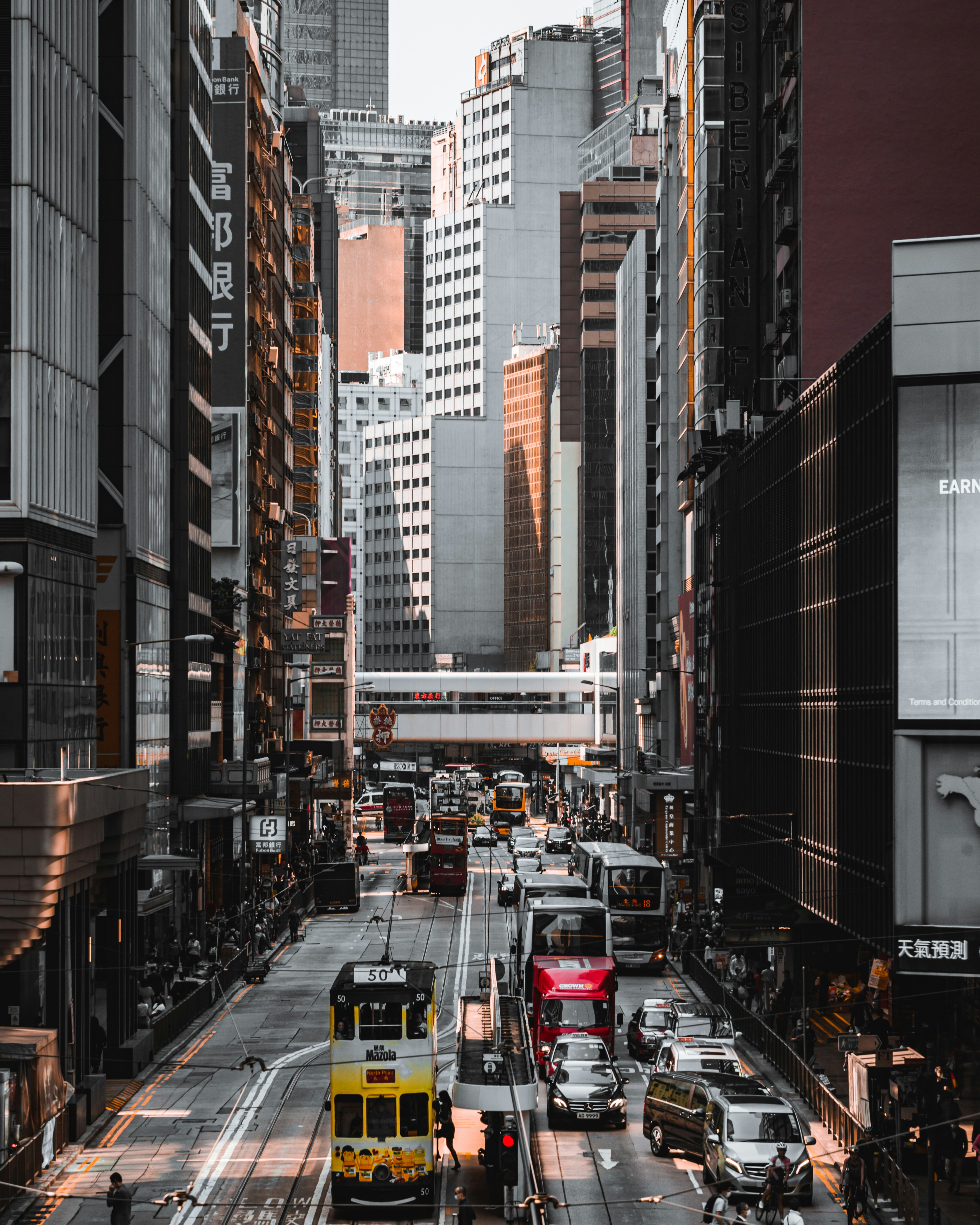 Bustling street scene in an urban environment, showcasing a mix of vehicles and towering skyscrapers. The composition highlights the dynamic nature of city life.