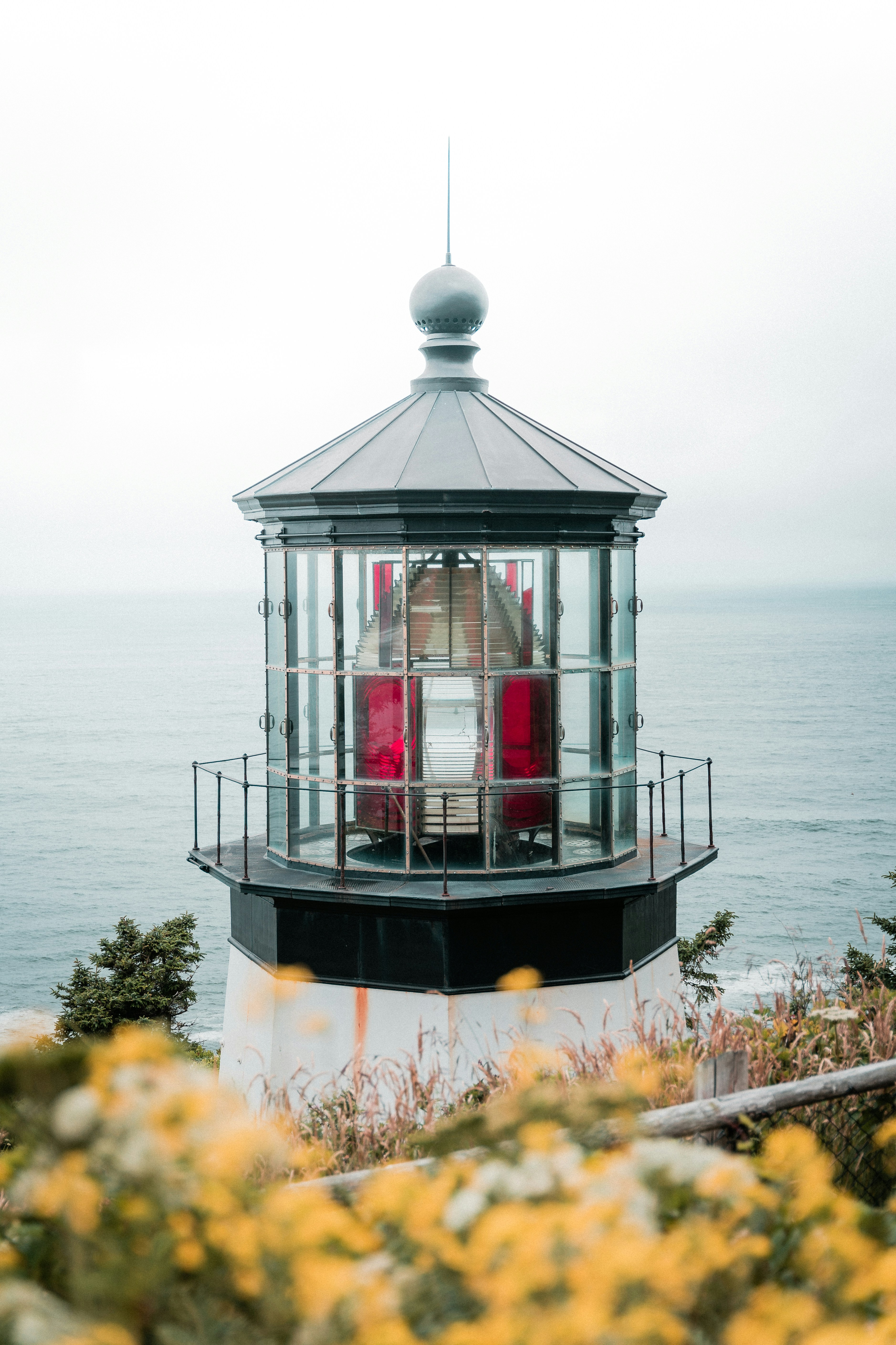 Red and white lighthouse on brown rock formation near body of water ...