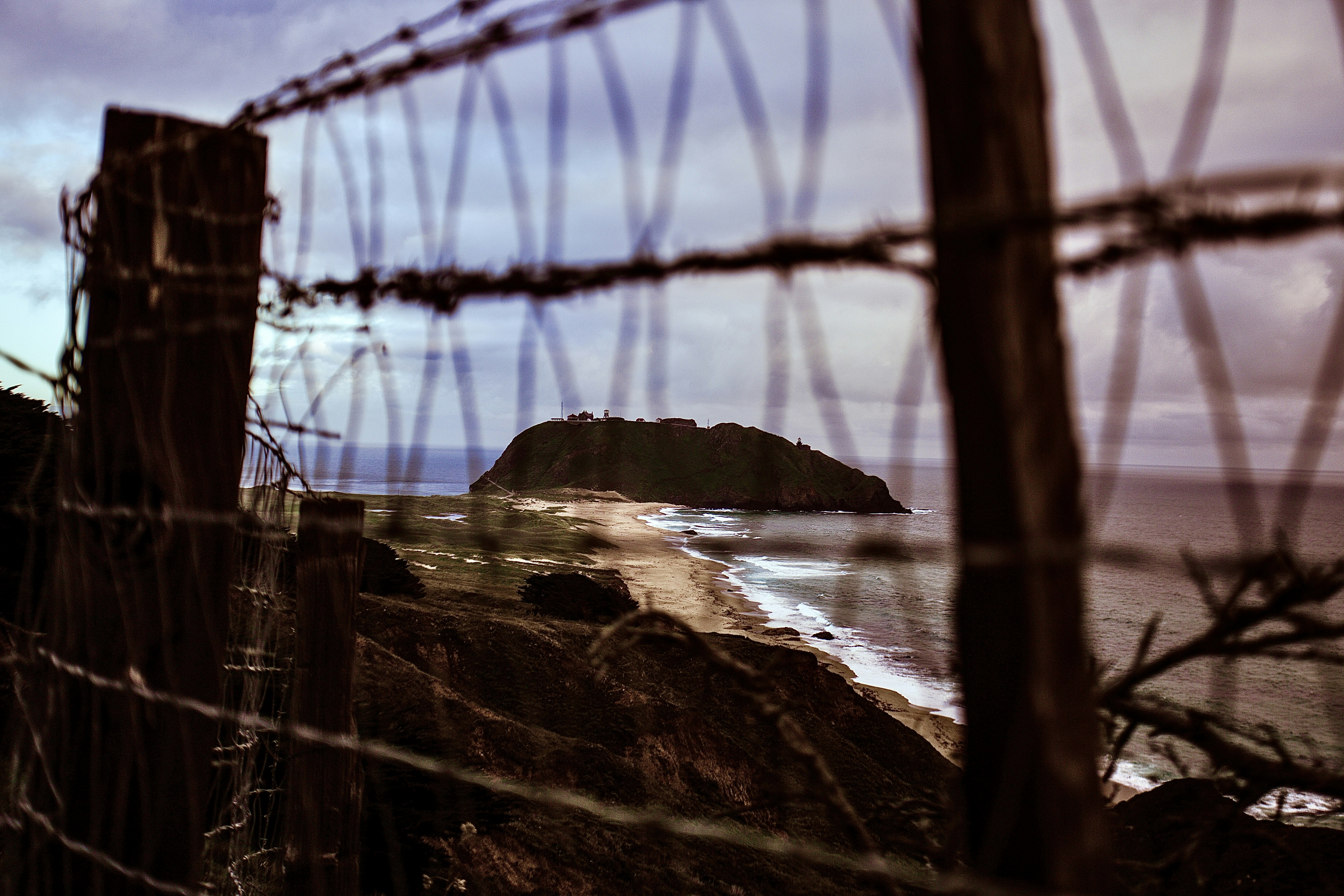 Barbed Horizon: Coastal Gate beneath Razorwire