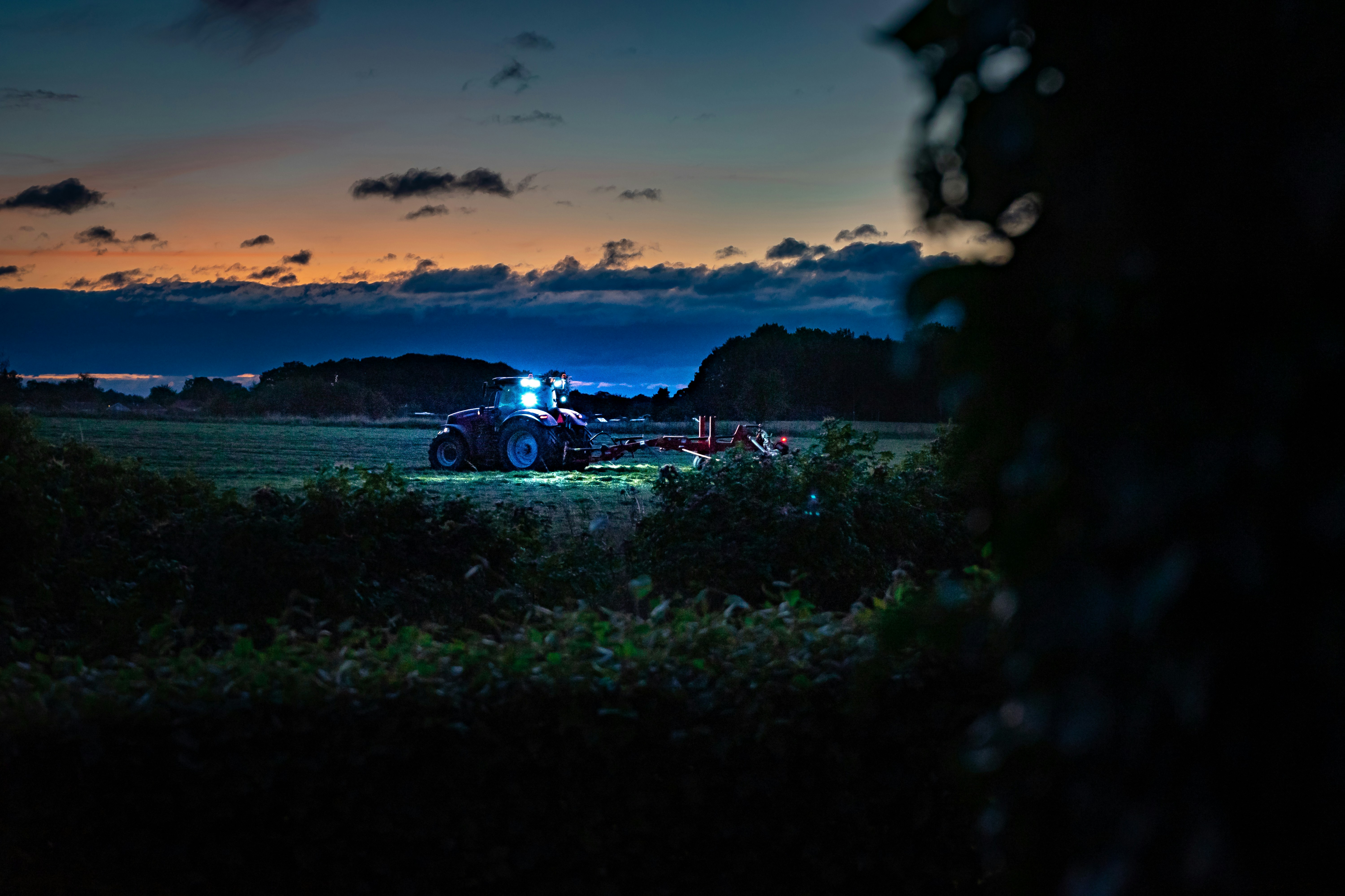 Dusk Fieldwork: A Tractor's Blue Beacon Illuminates the Quiet Horizon