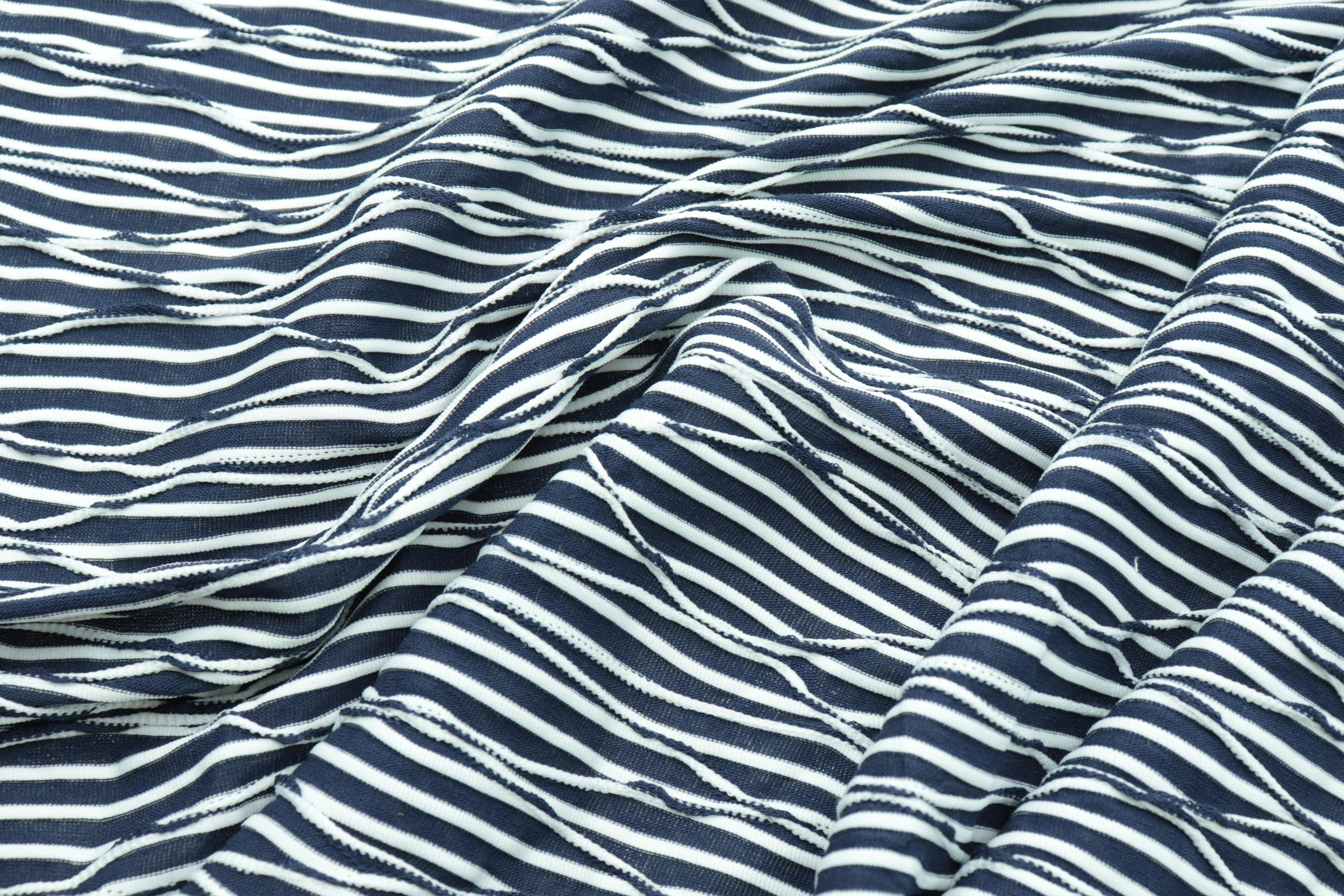 Close-up of navy fabric with white stripes, showcasing intricate texture and patterns.