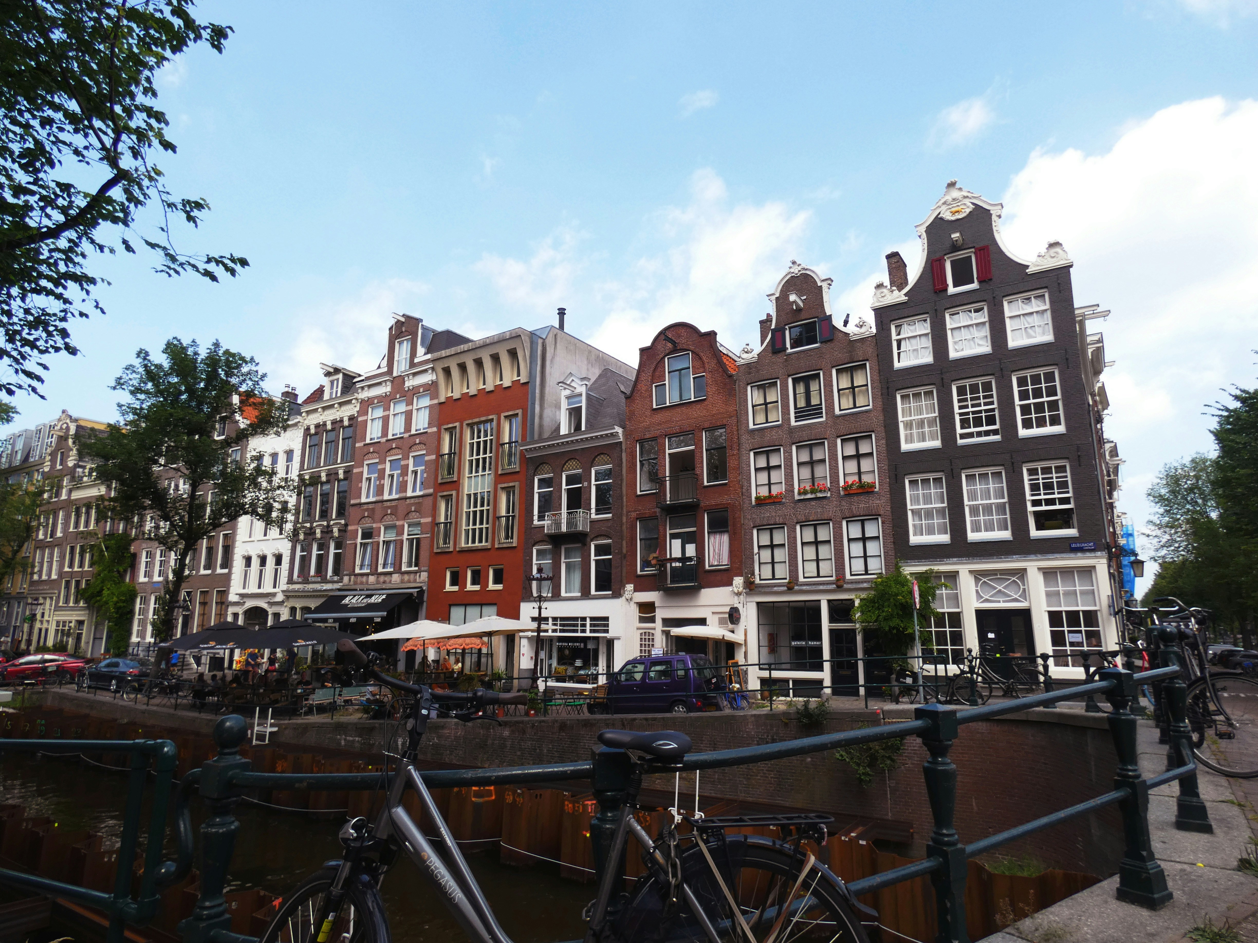 Historic canal-side buildings in Amsterdam showcase unique Dutch architecture with vibrant colors and intricate designs.