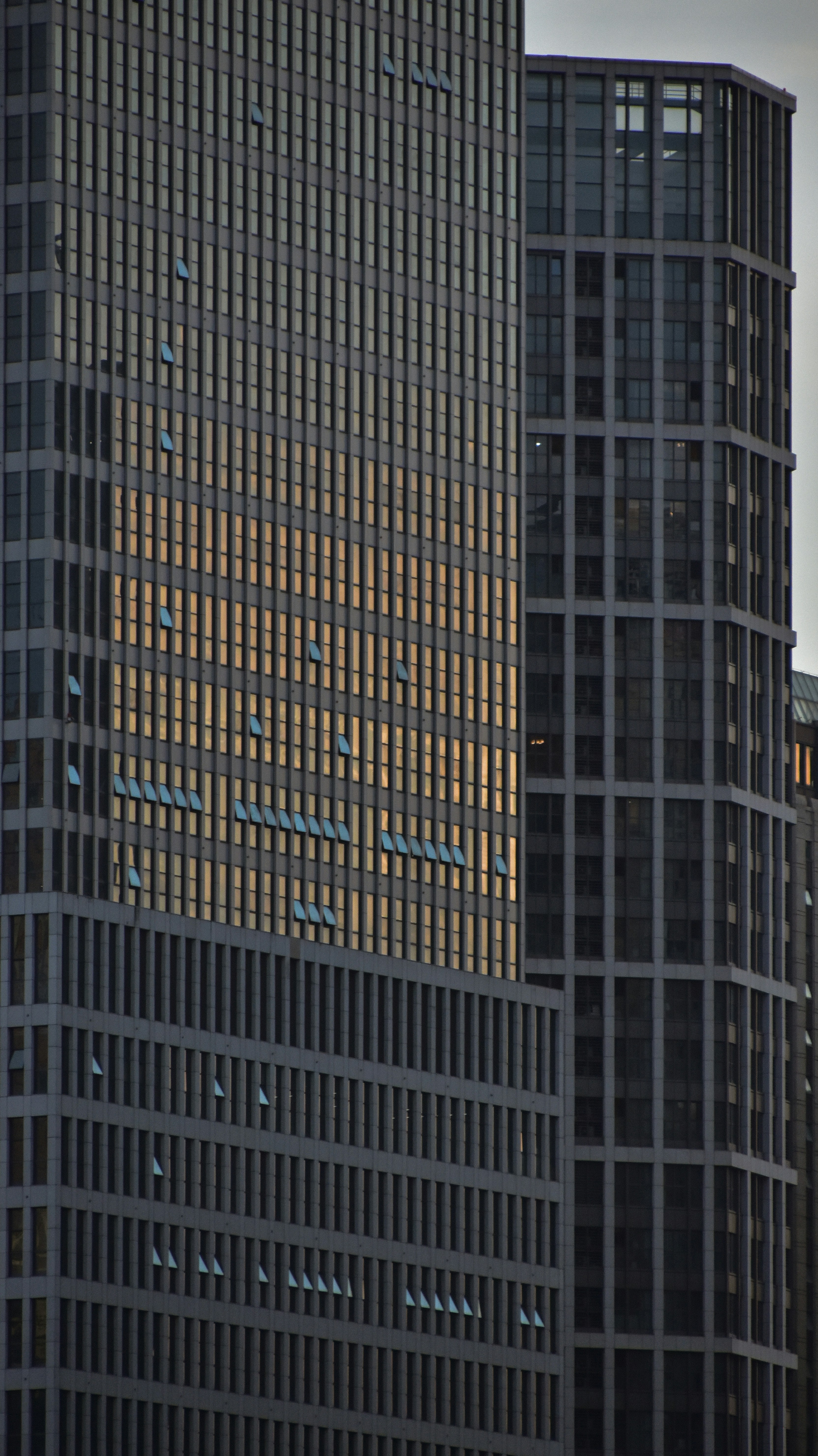 Close-up of modern skyscraper facades showcasing reflective glass and geometric patterns. The interplay of light and shadow creates a dynamic urban tapestry.