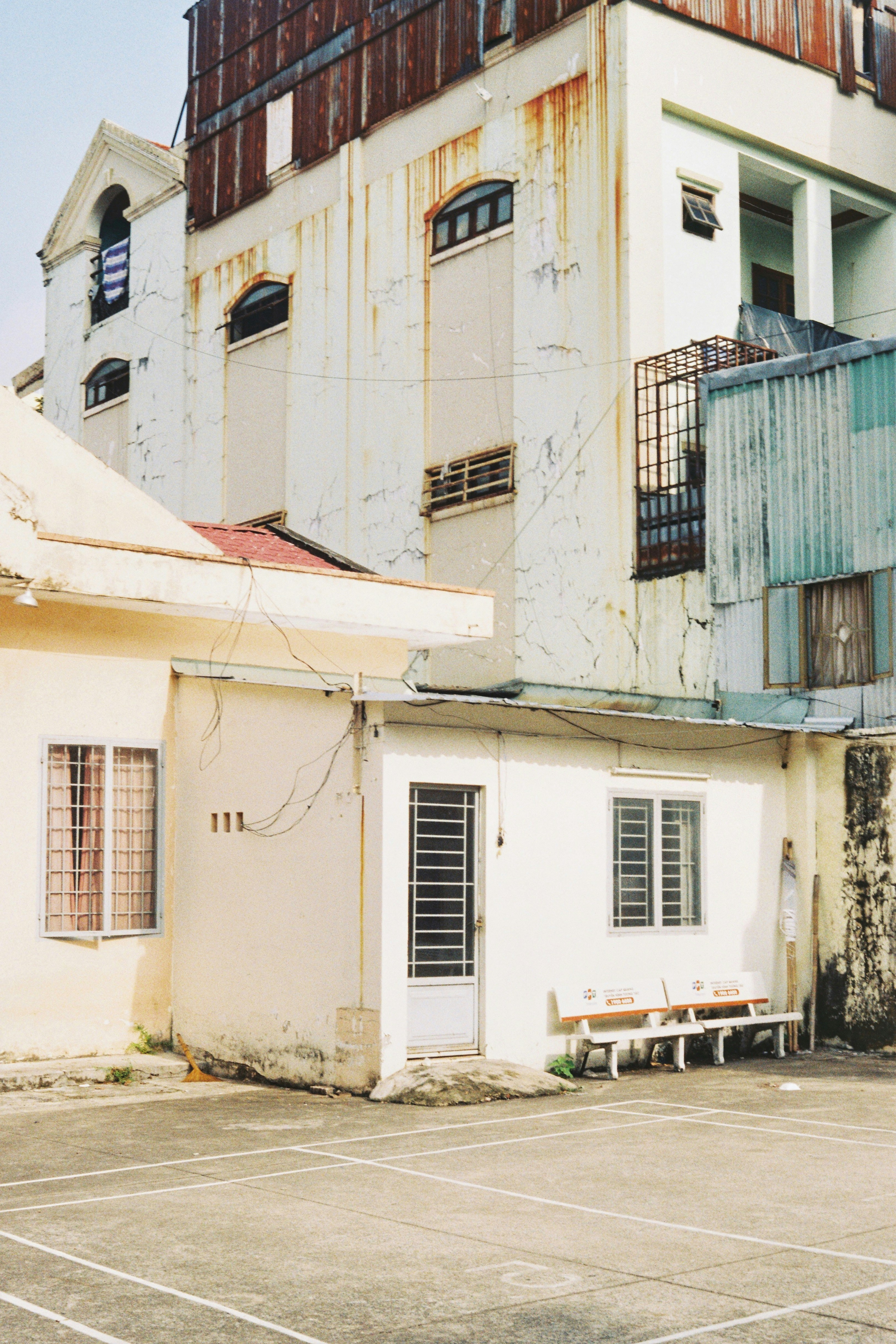 Sunlit Courtyard Facade: Weathered White Walls and Rusted Accents