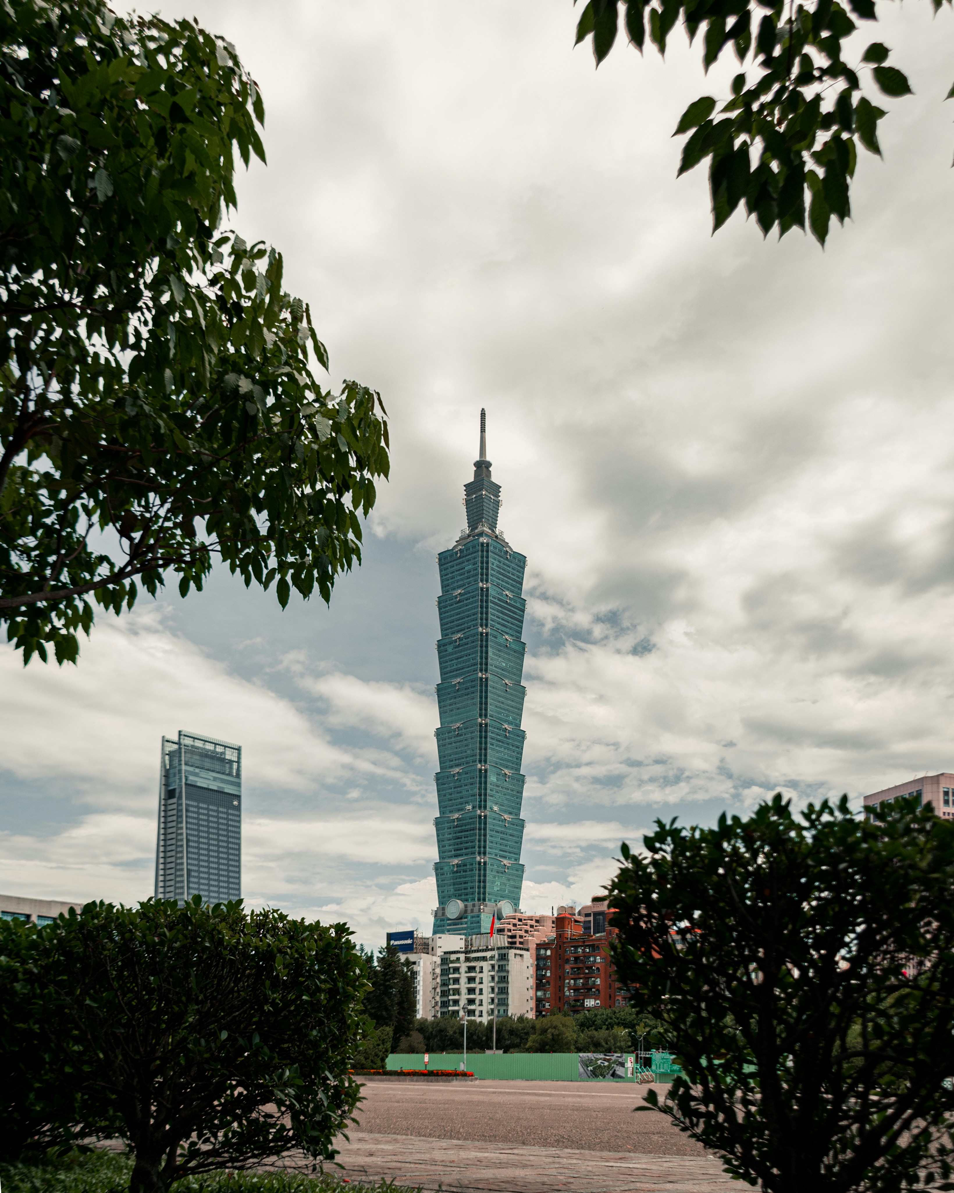 Taipei 101 tower rises amidst lush greenery and urban architecture, showcasing the blend of nature and city life.