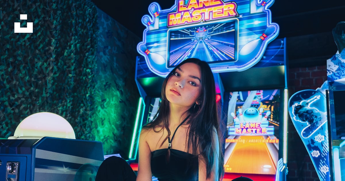파란색과 노란색 아케이드 기계에 앉아 검은 민소매 드레스를 입은 여자 사진 Unsplash의 무료 방콕 이미지