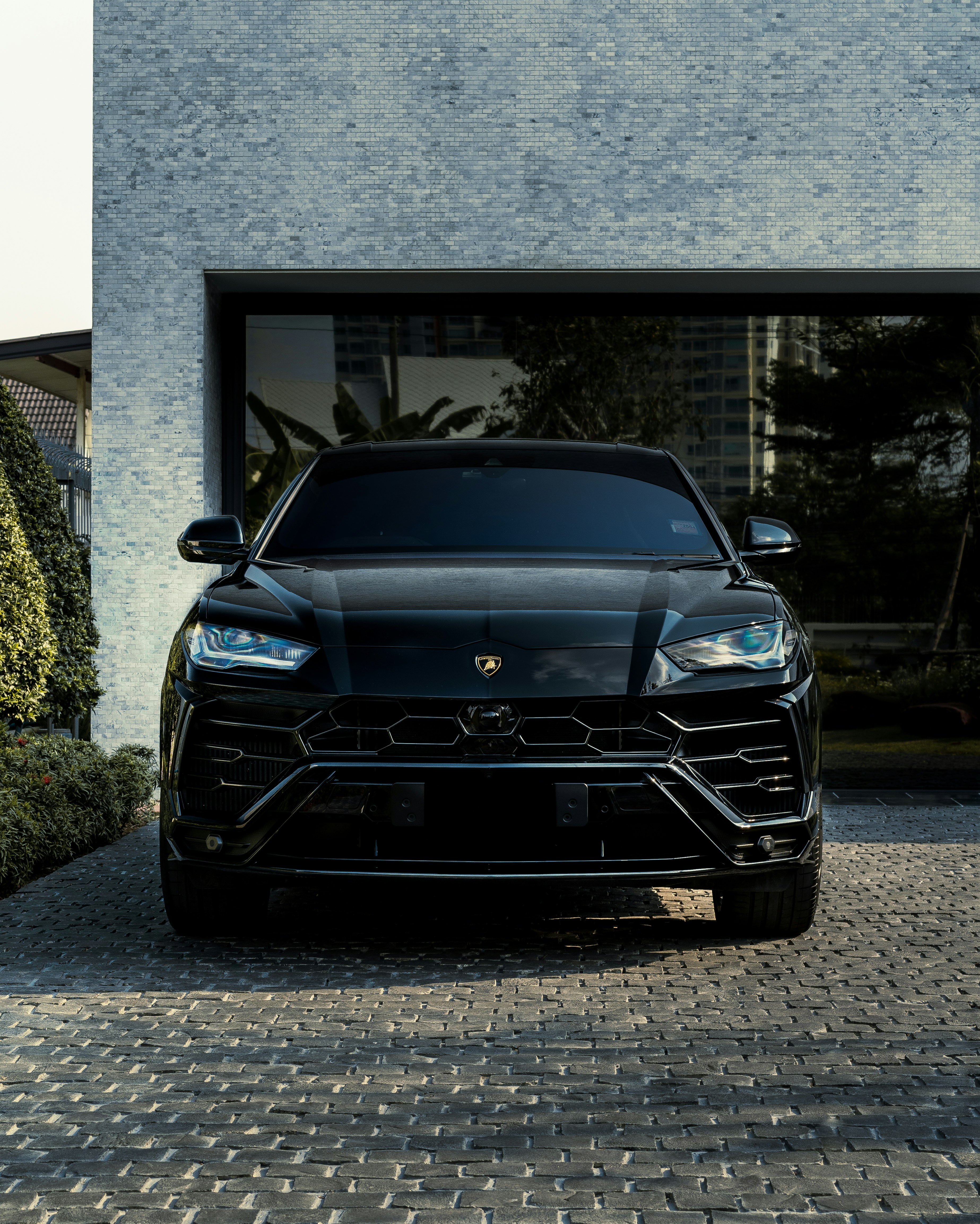 Sleek black Lamborghini Urus parked in front of a modern architectural backdrop, showcasing luxury and design.