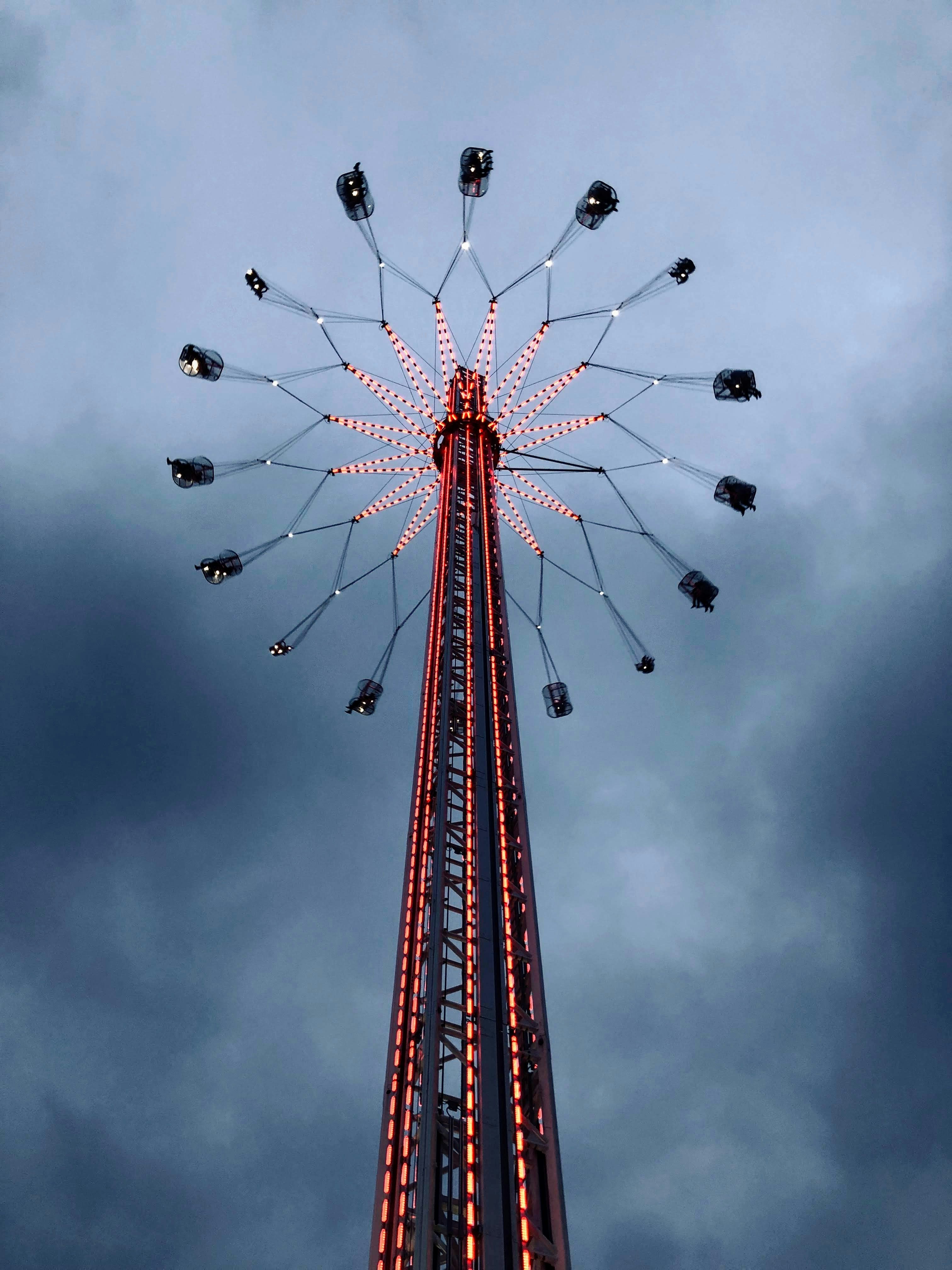A towering amusement ride adorned with vibrant lights against a moody sky, capturing the essence of excitement and adventure.