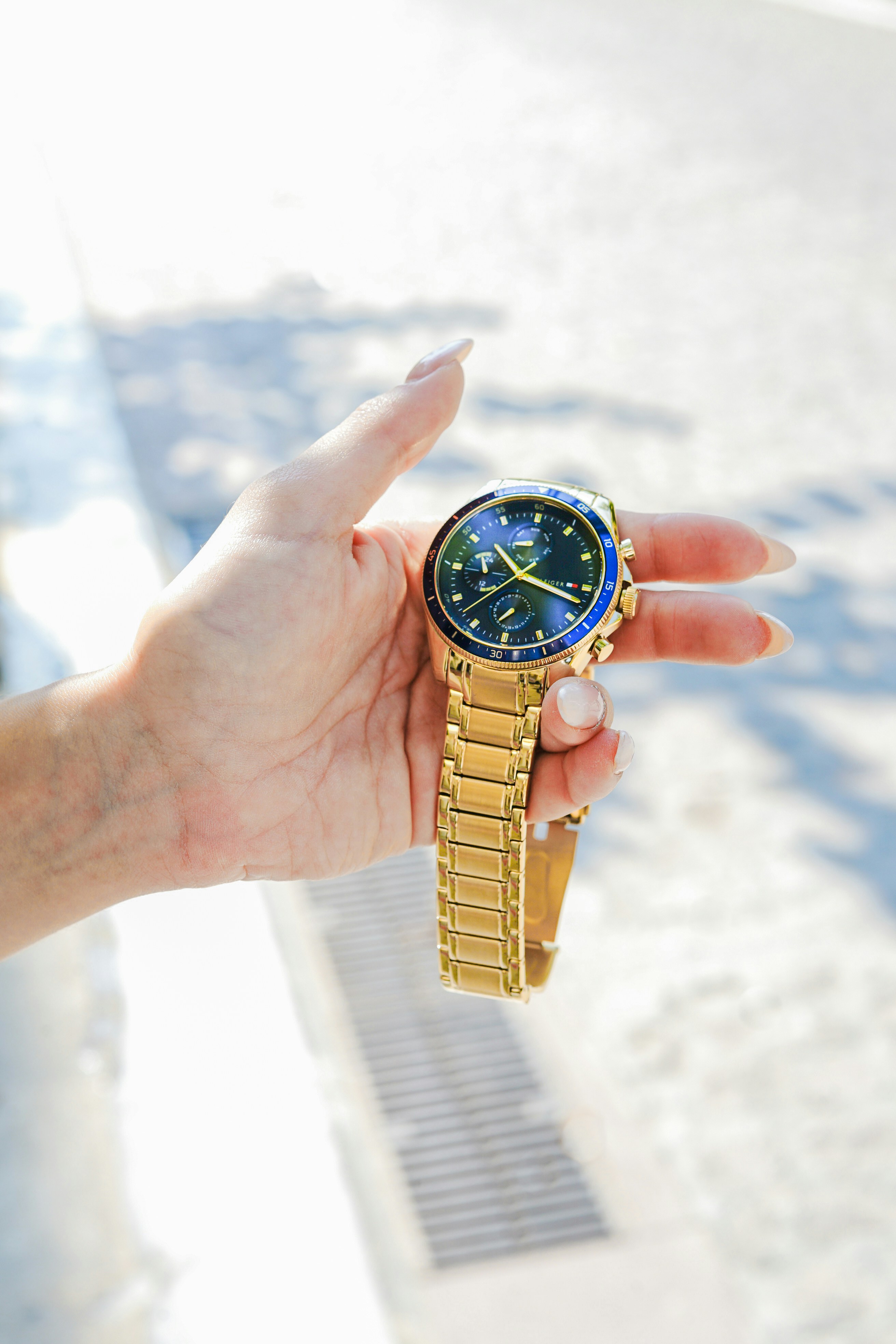 A hand holding a luxurious gold watch with a dark blue dial, showcasing intricate details and a contemporary design.