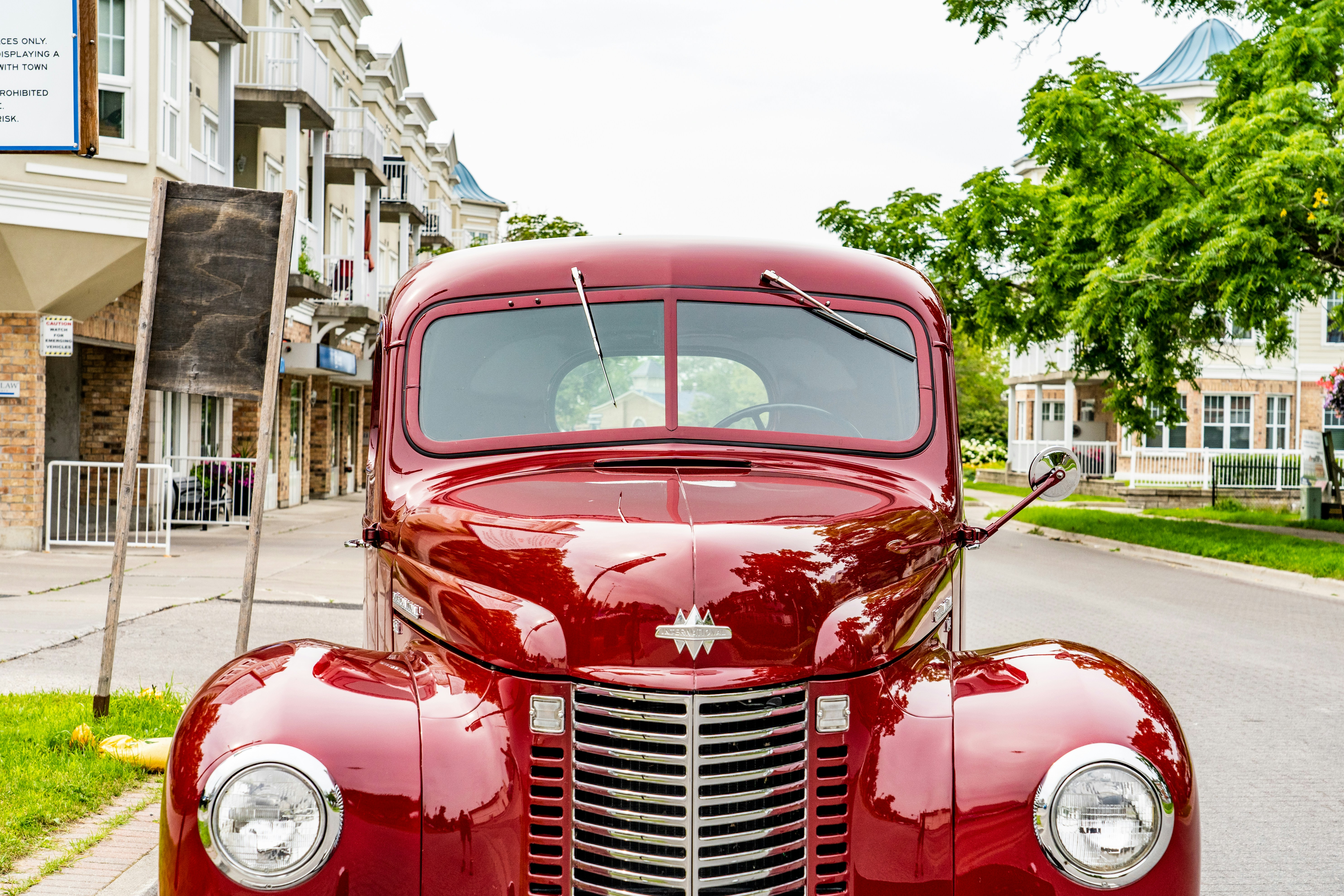 Classic red truck parked on a city street, showcasing its vintage design against a backdrop of modern buildings.