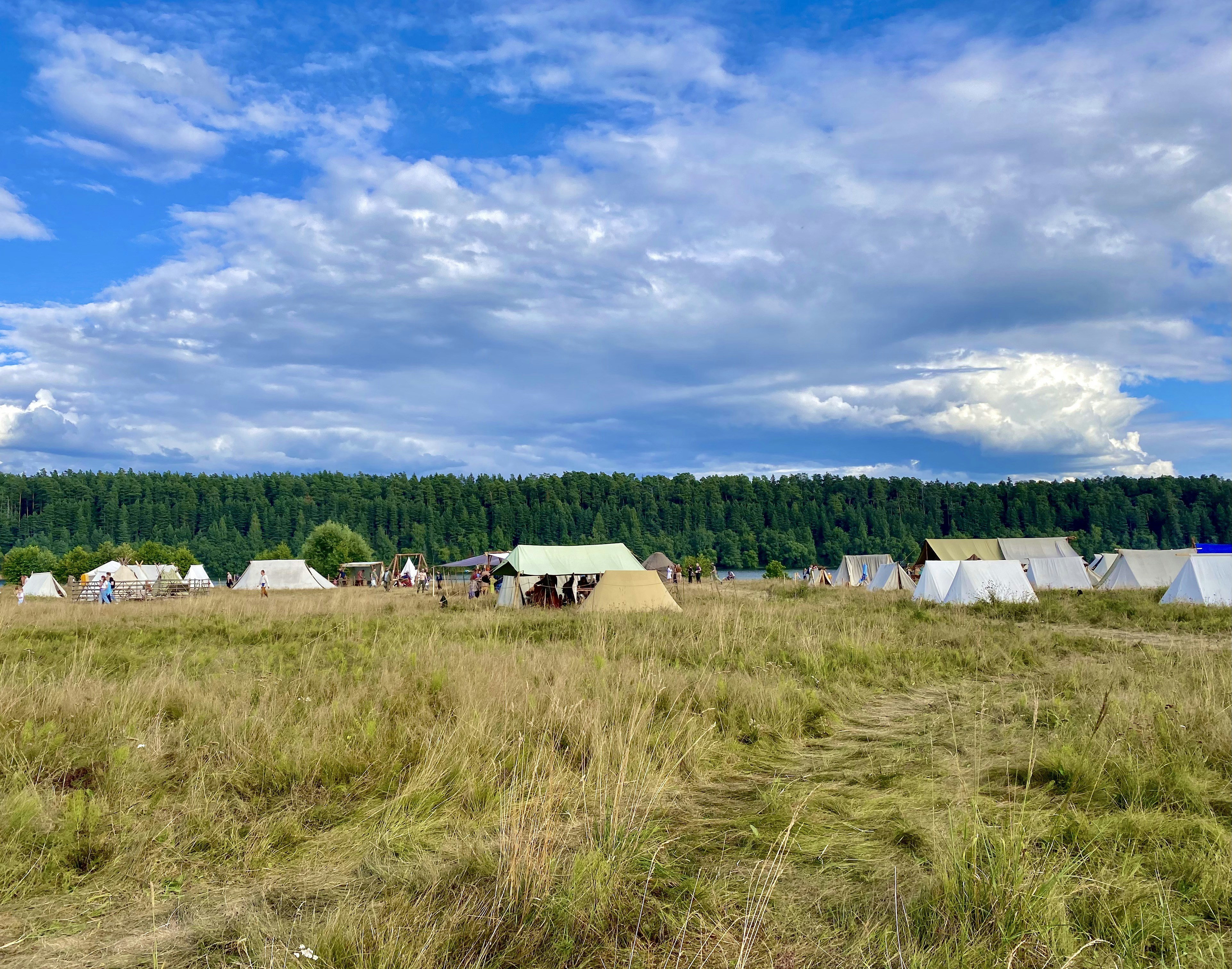 Row of Tents in a Wide-Open Meadow Under a Cloud-Patched Sky