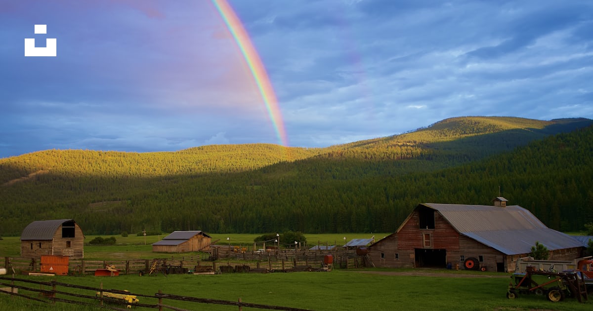 昼間の虹と白い雲の下の緑の草原の近くの茶色の木造住宅の写真 Unsplashの無料アイダホ写真
