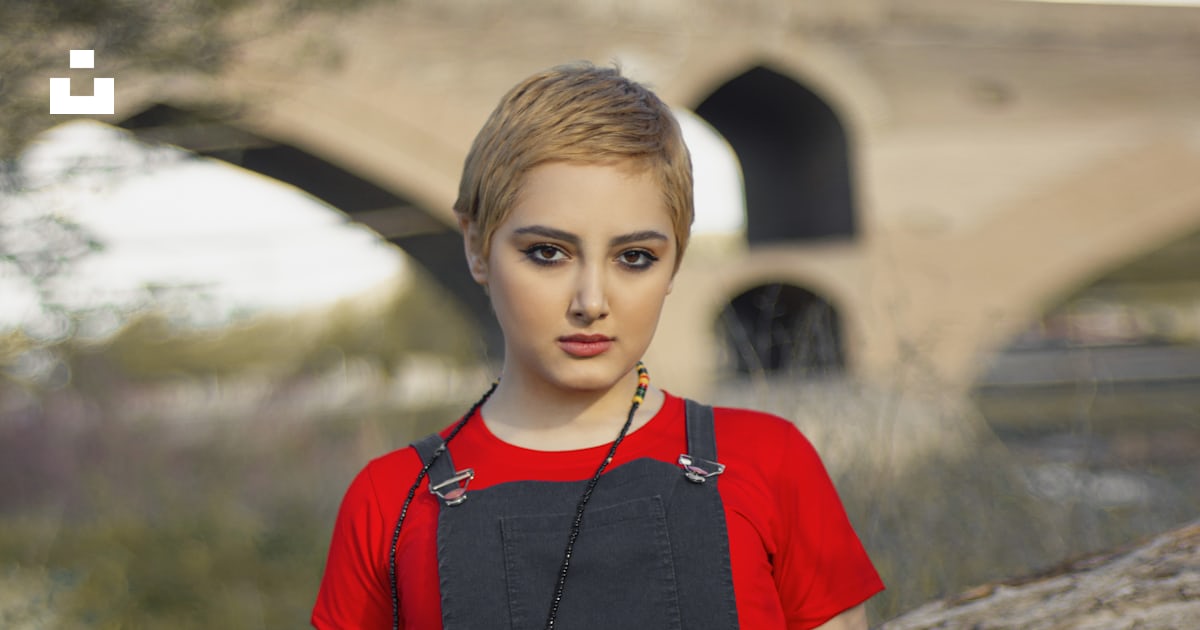 赤いクルーネックのtシャツと黒のデニムジーンズの女の子が緑の芝生の上に立っていますの写真 Unsplashのザンジャーンの無料画像