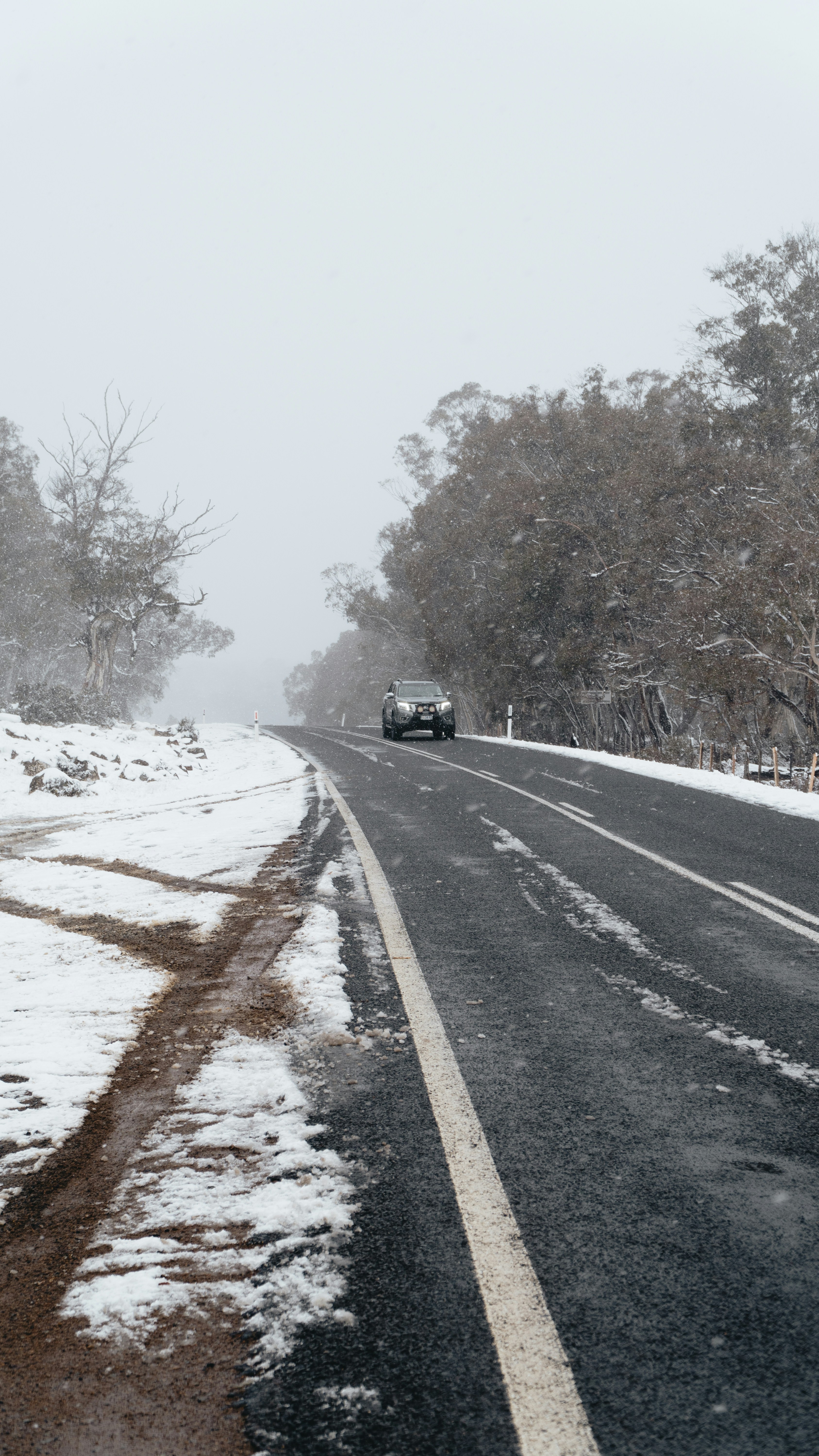 Snowbound Highway: A Lone Vehicle Traverses a Misty Winter Road