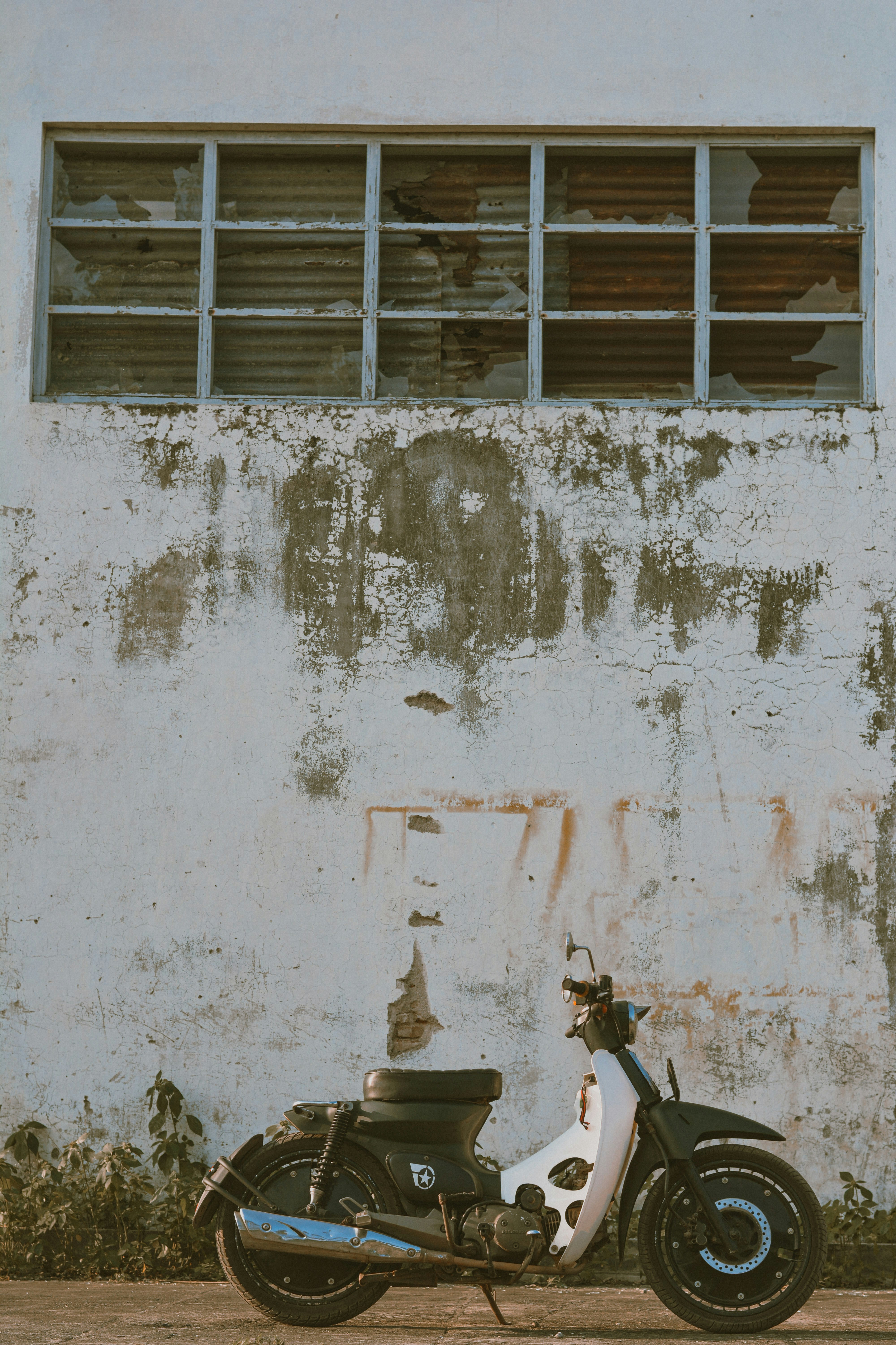 Blue-Rimmed Vintage: A Scooter Pauses Before a Weathered Facade