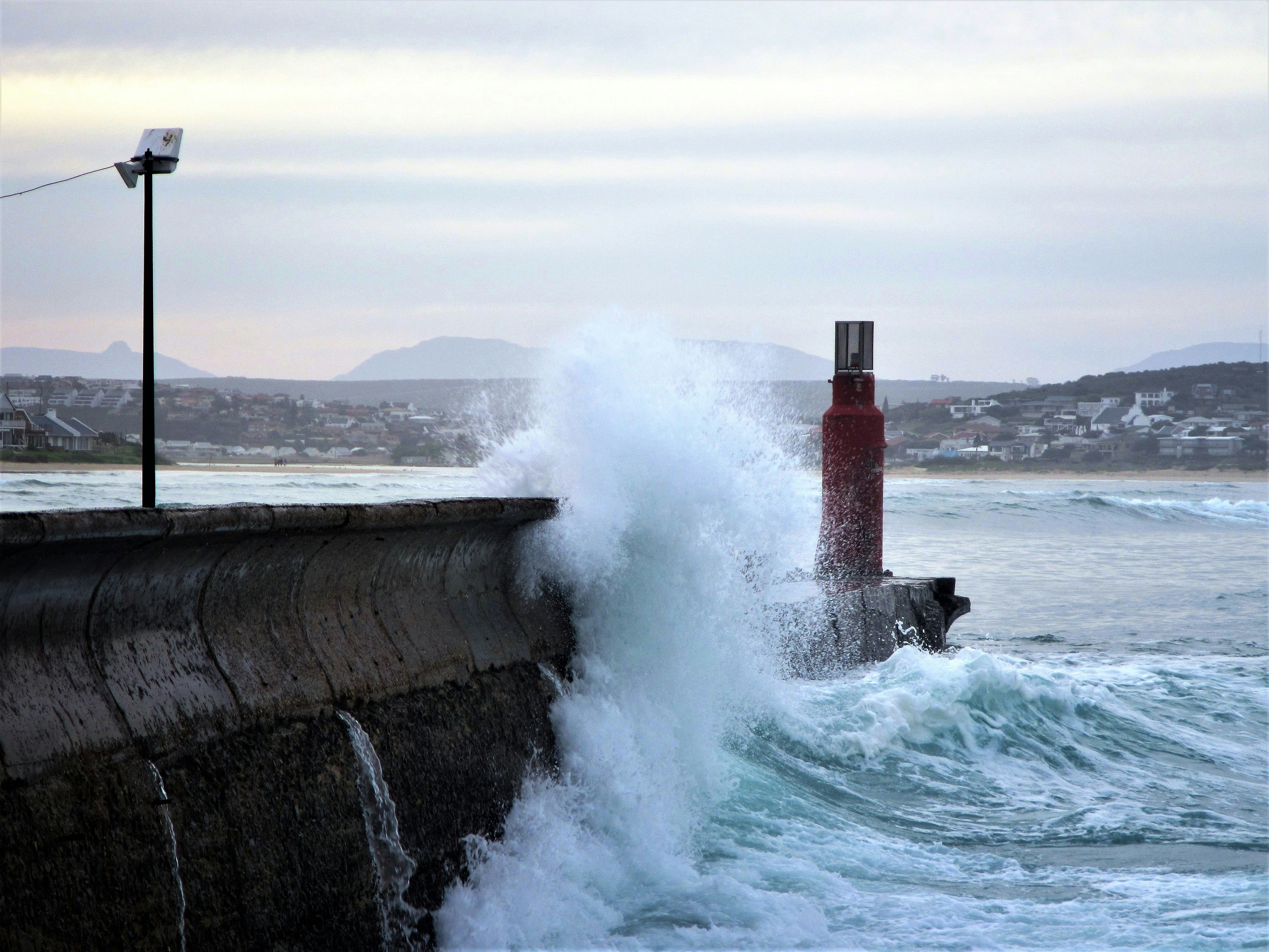Red and black lighthouse on rock formation near sea during daytime ...