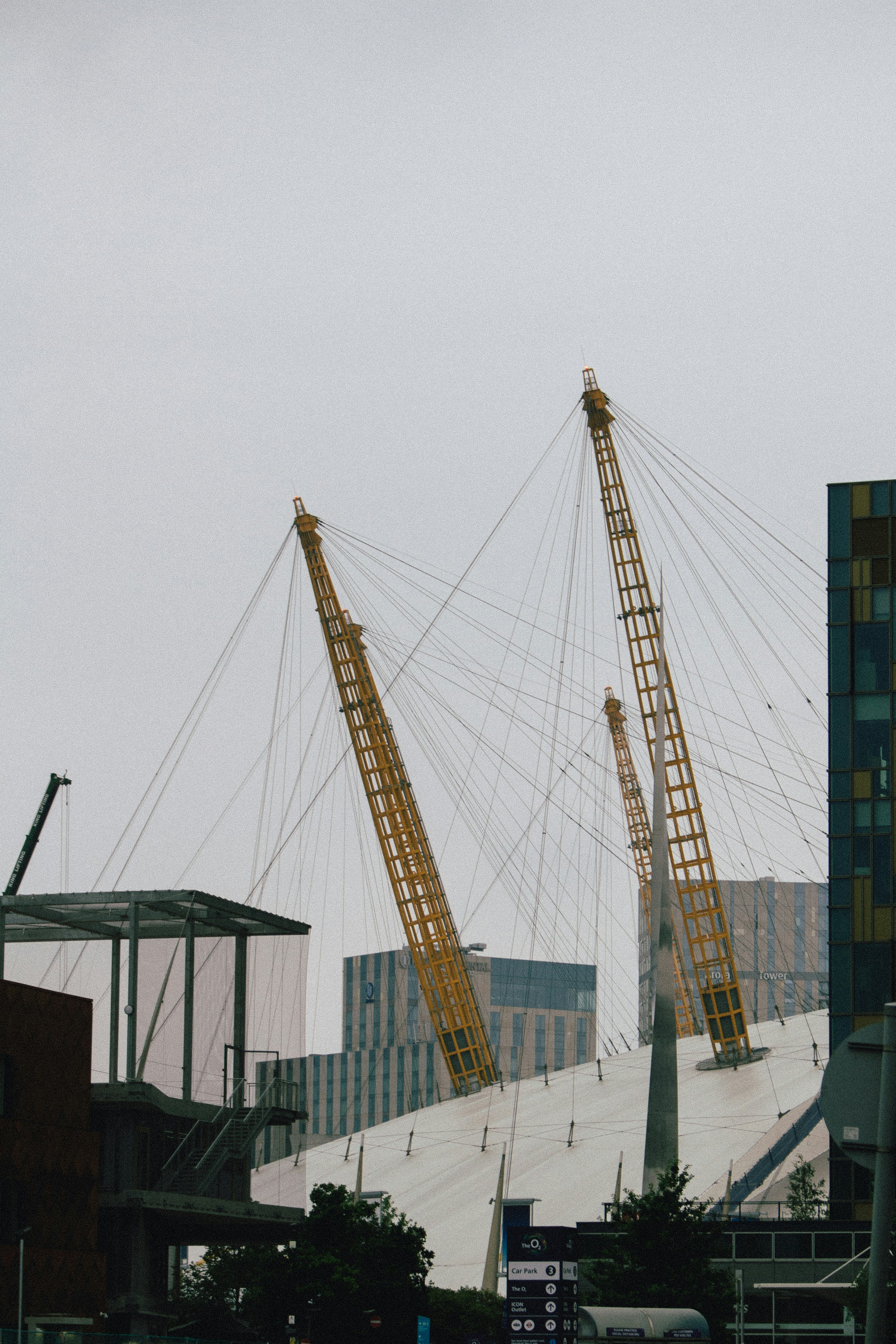 Golden Crane Masts Span a Modern Roof under a Pale Sky