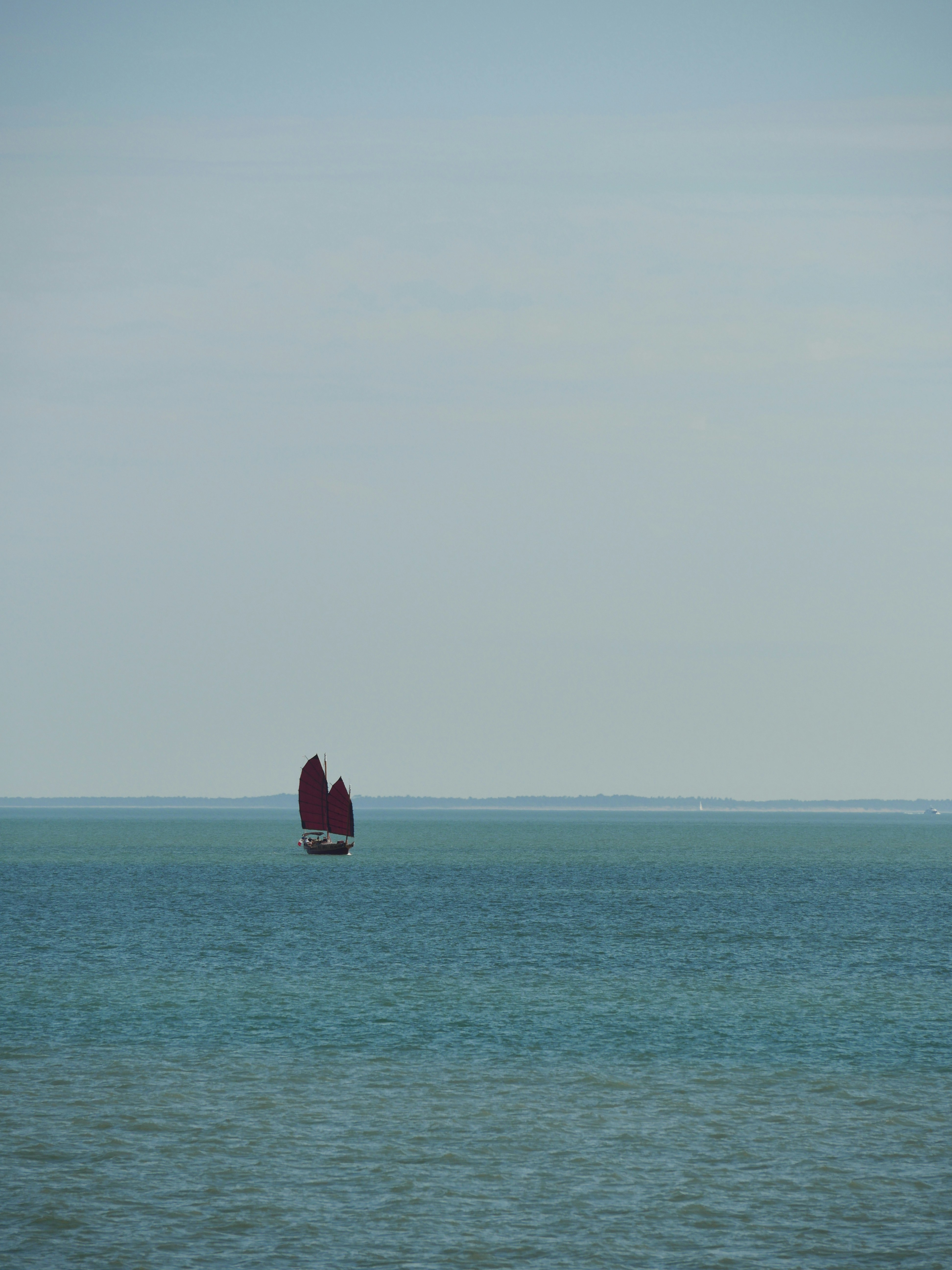 Sailboat on a Quiet Sea under Open Sky