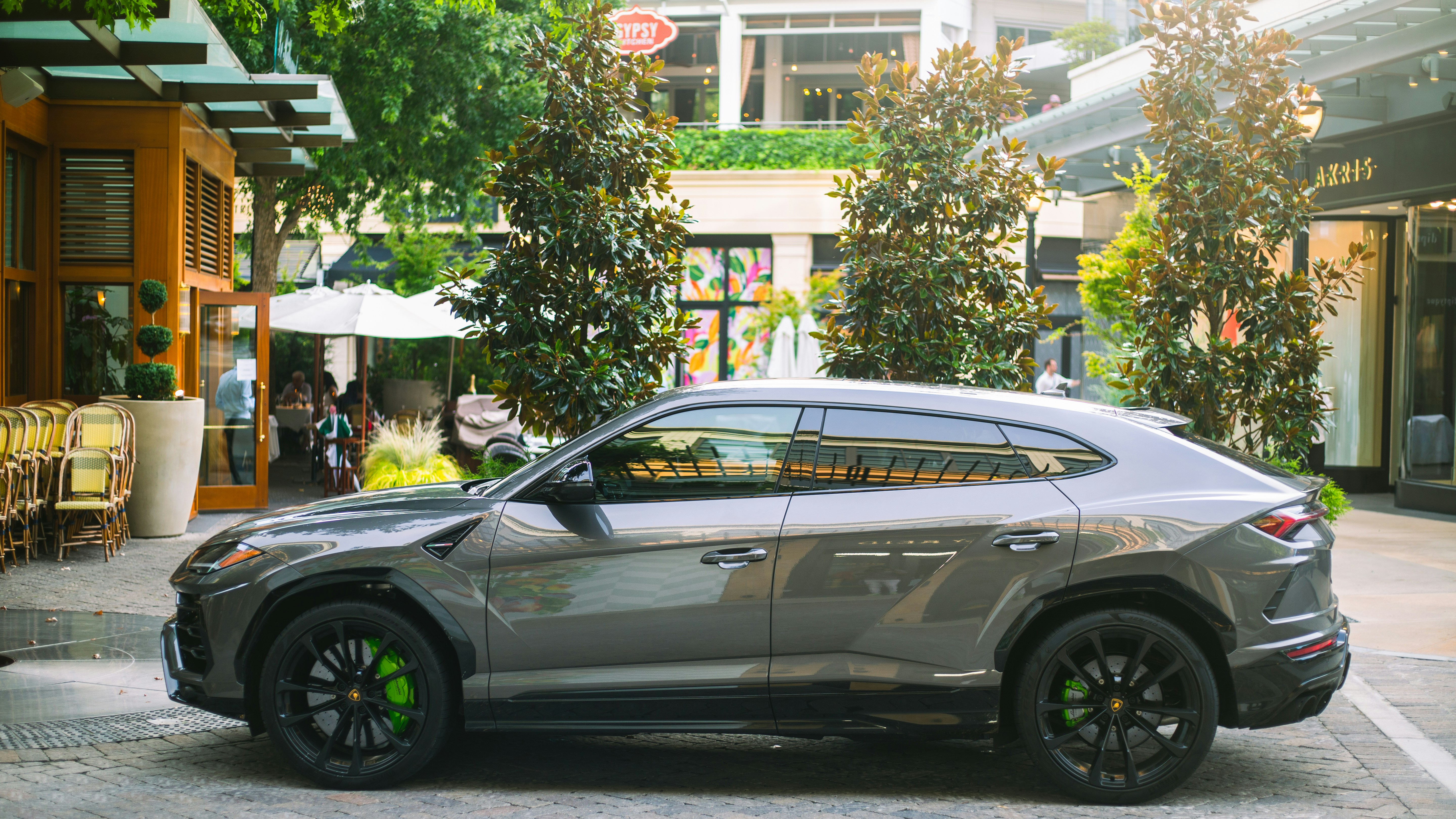 black sedan parked beside green tree during daytimeOsarugue Igbinoba