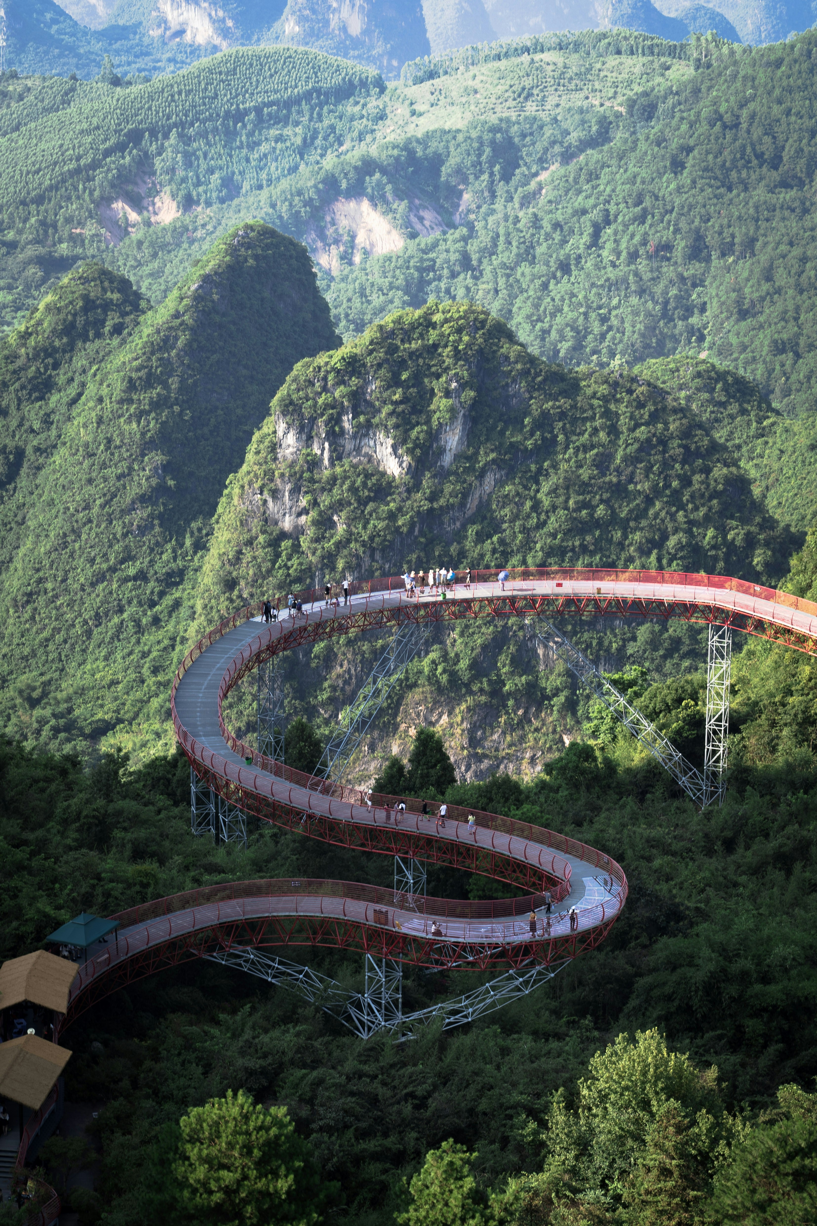 A winding observation walkway curves through lush green mountains, inviting visitors to explore the scenic landscape.