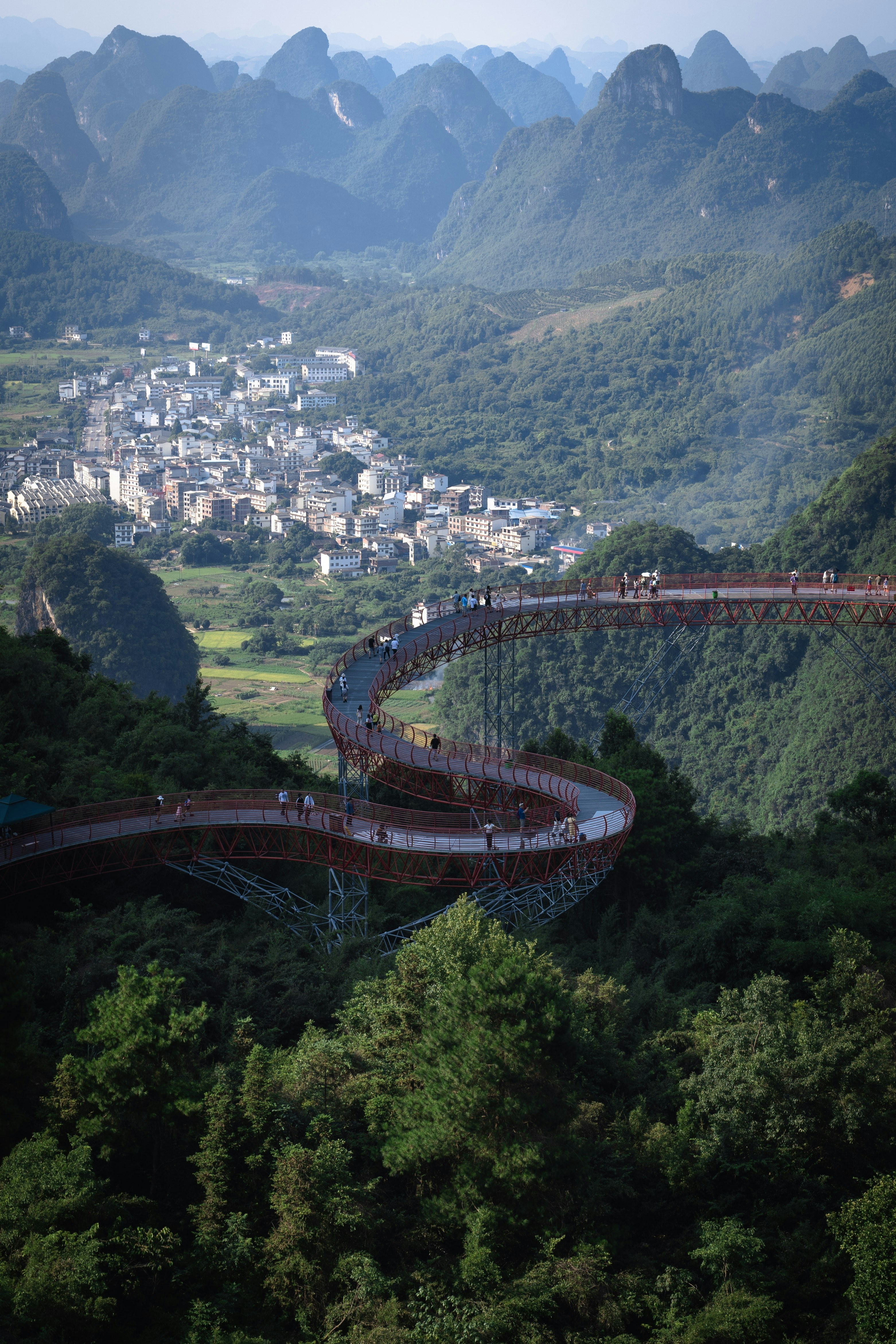 Spiral Skyward: The Red Walkway Curling Through Misty Limestone Valleys