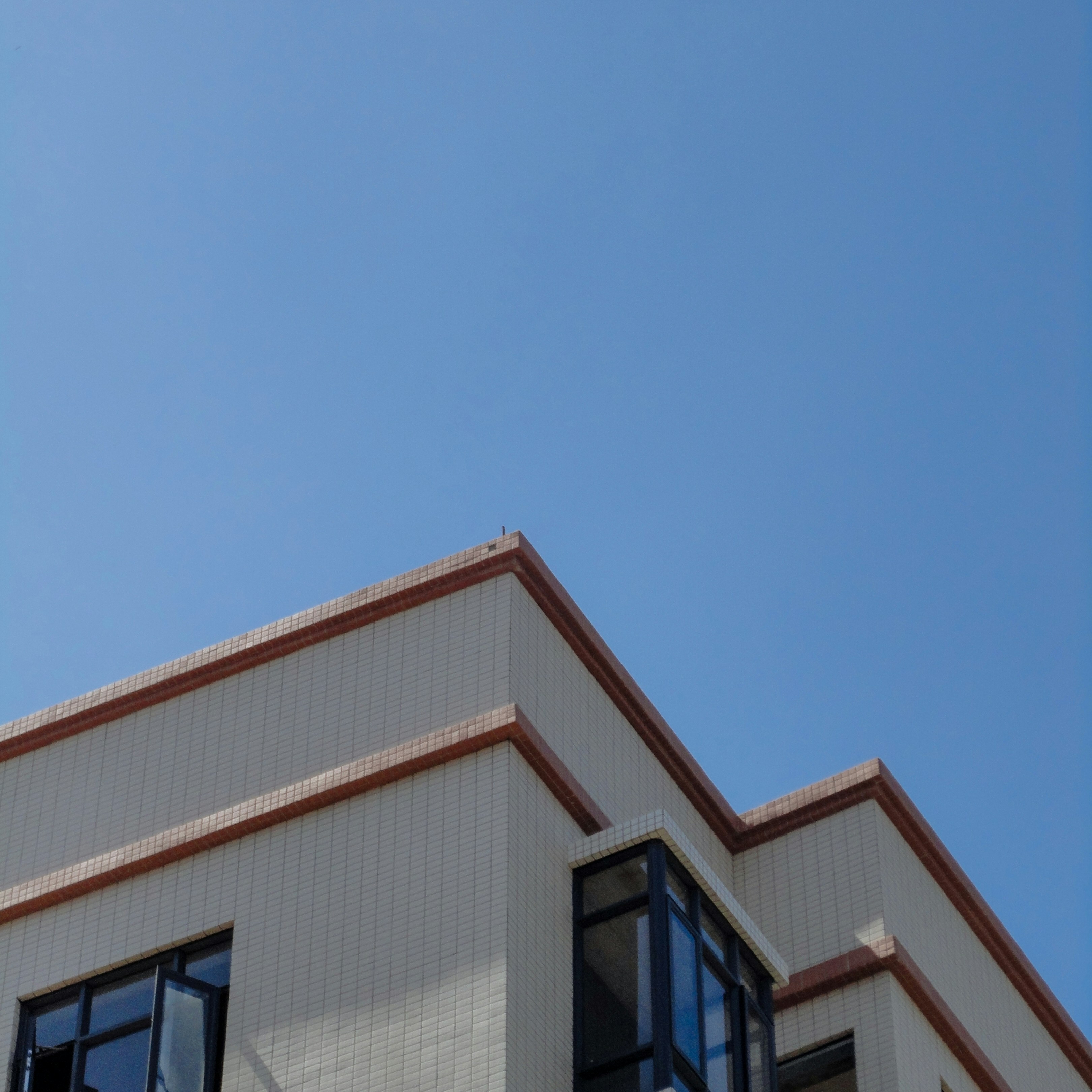 Contemporary building facade with prominent windows and clean lines under a bright blue sky.