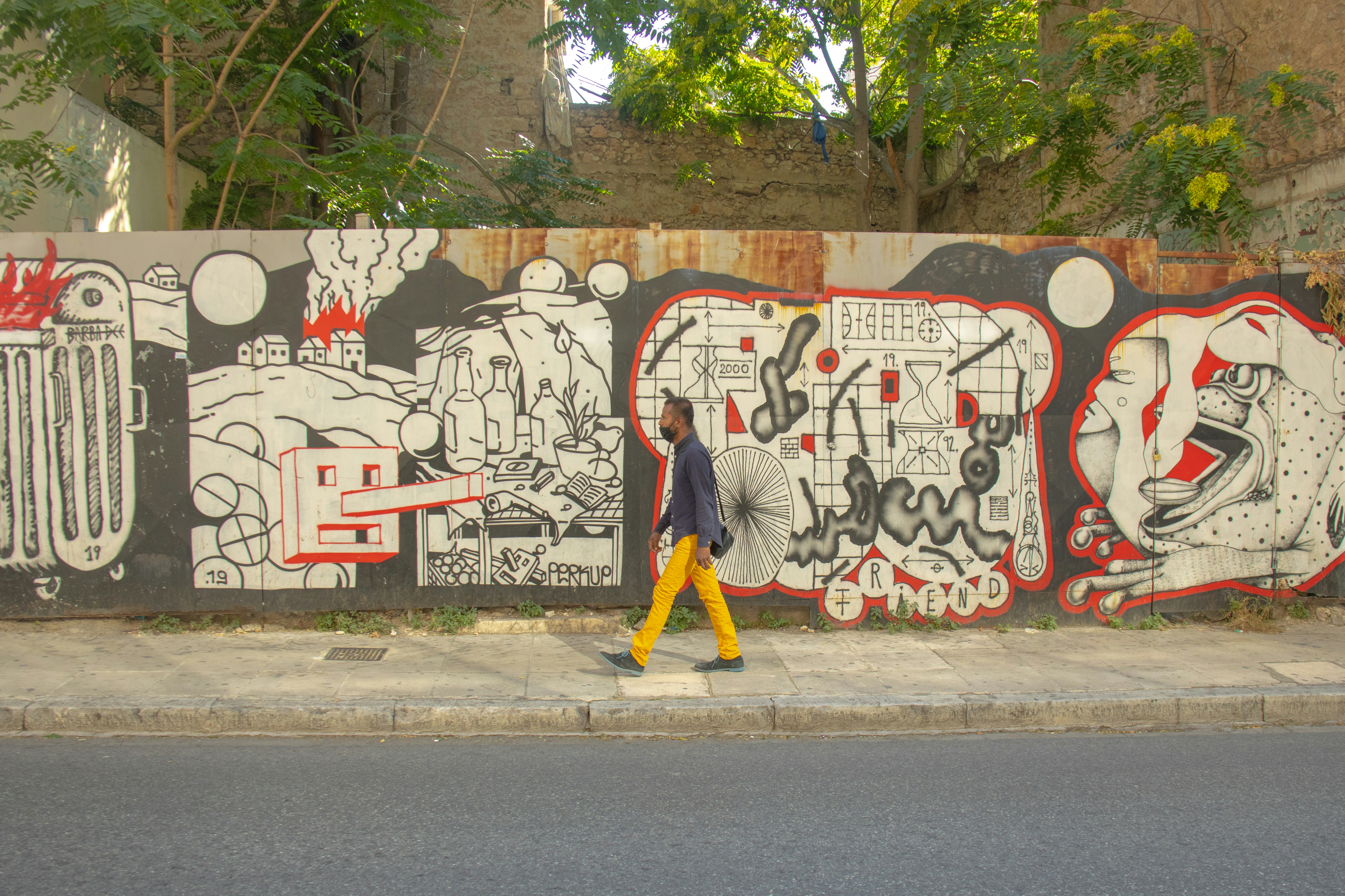 Yellow-pants stride past a mural of urban myths