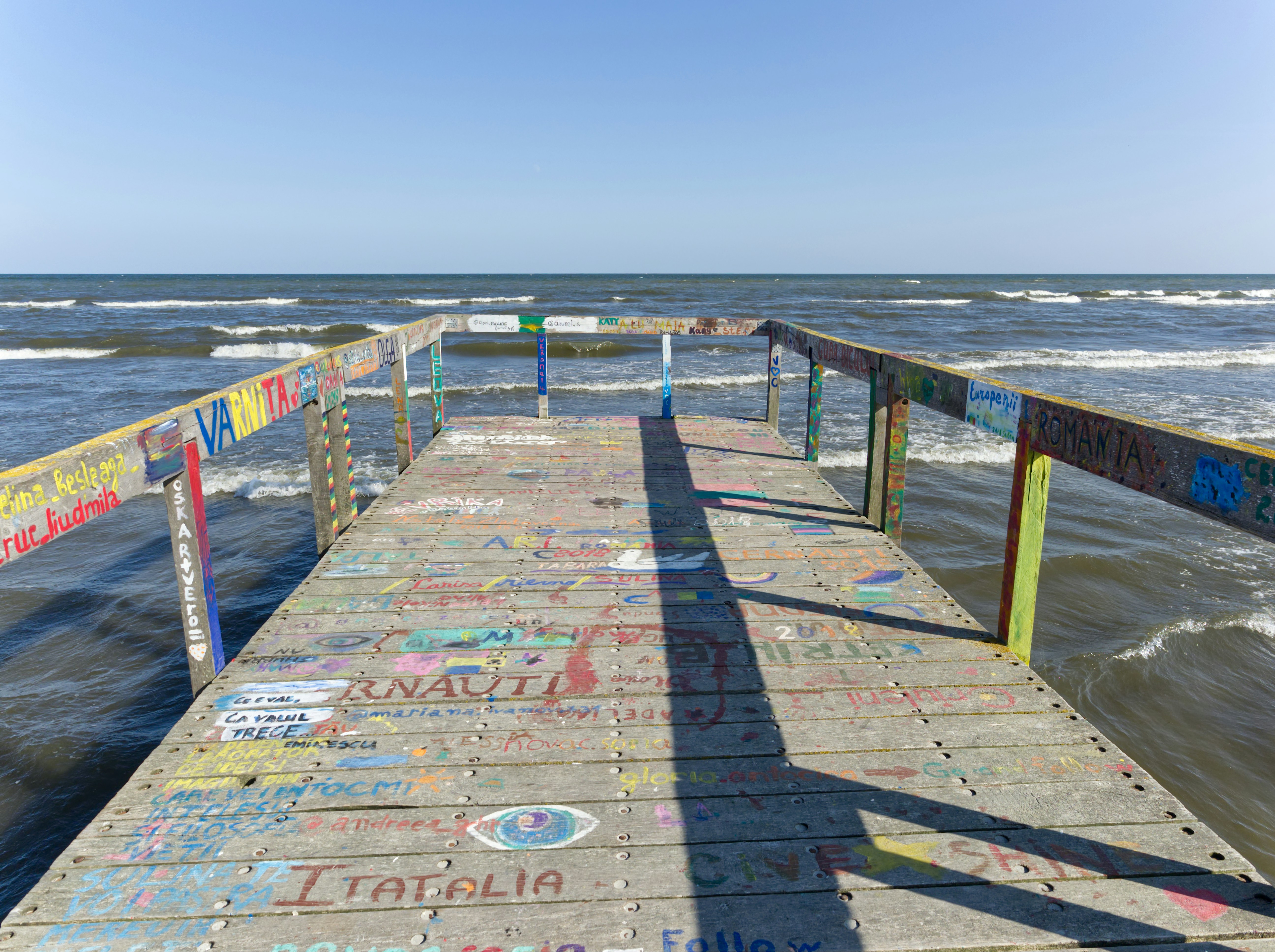 Graffiti Pier to the Sea: A Sunlit Walkway of Color and Shadow