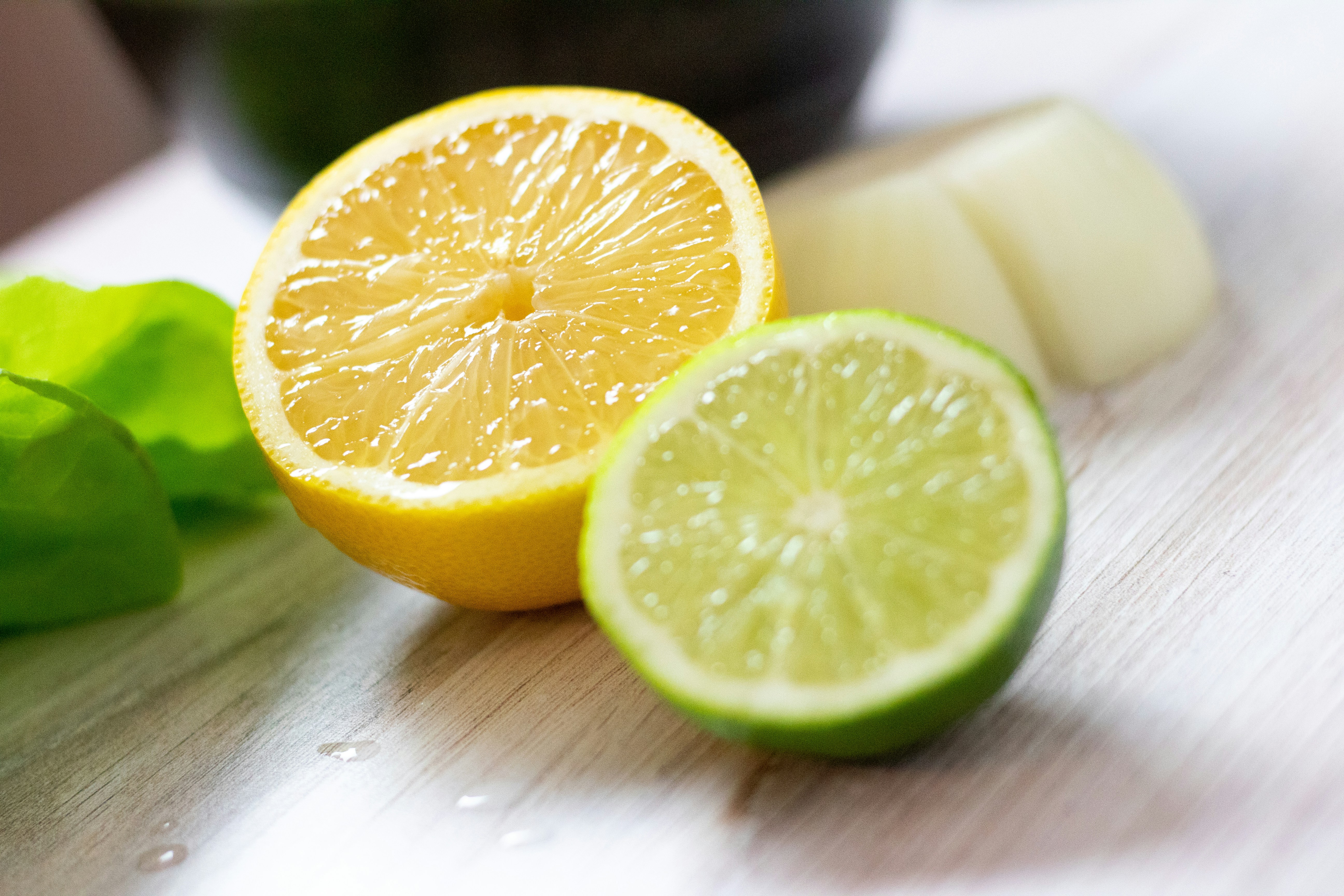 Halved lemon and lime on a wooden surface with blurred background.
