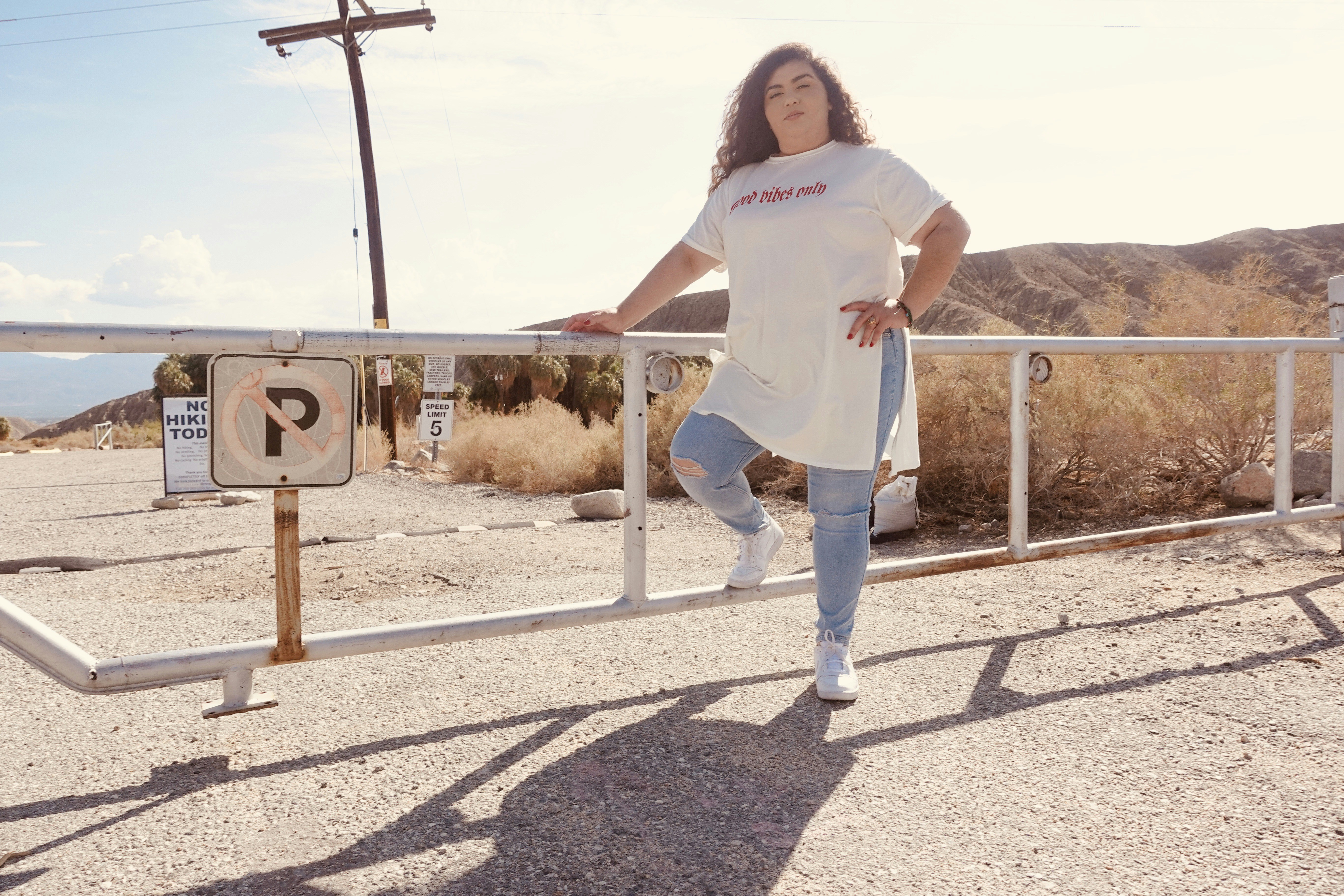 Desert Roadside Confidence: A Woman in White Stands by the Rail