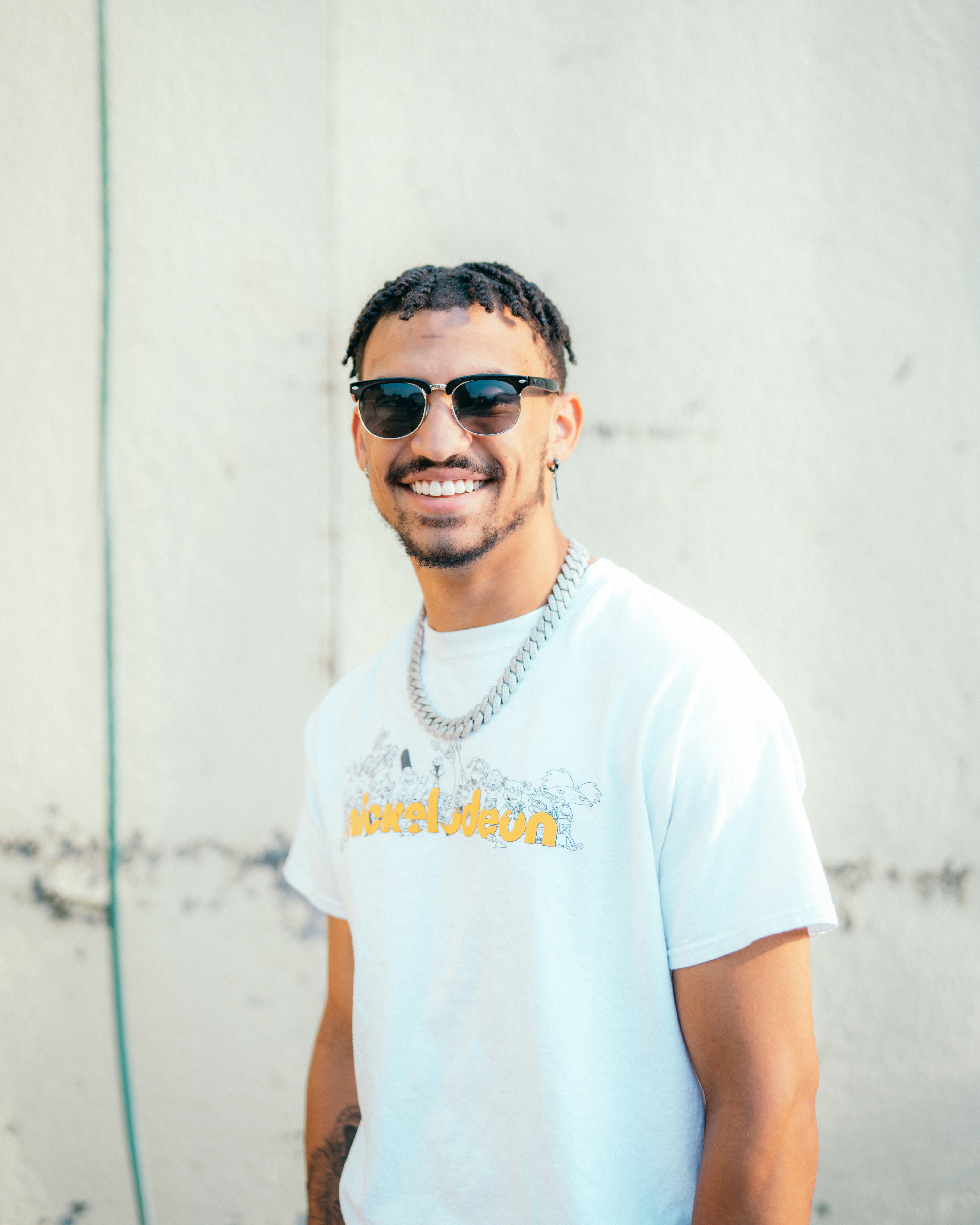 Neon-White Tee, Cool Gaze: A Street Portrait Against Pale Concrete
