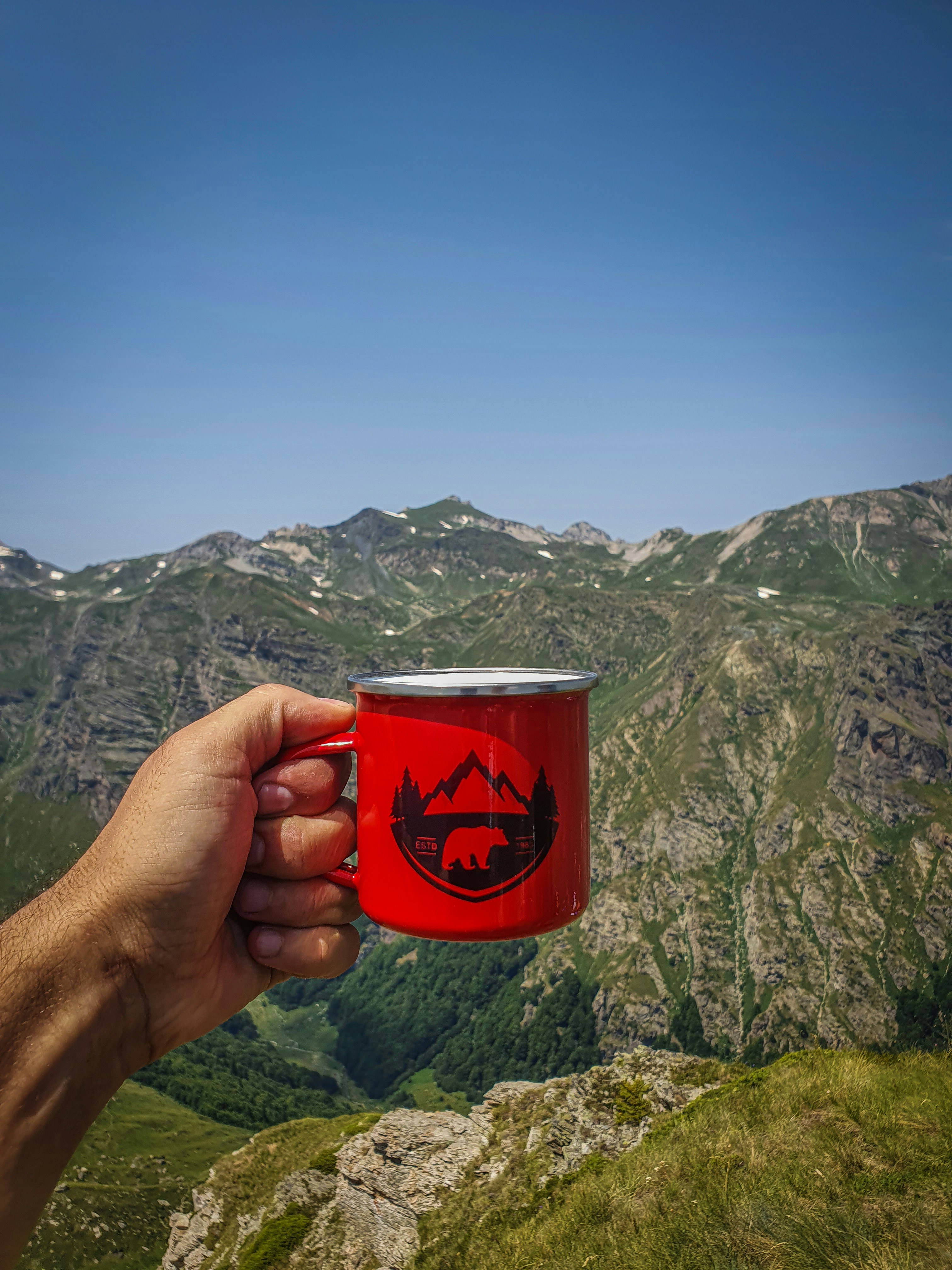 person holding red and white ceramic mug