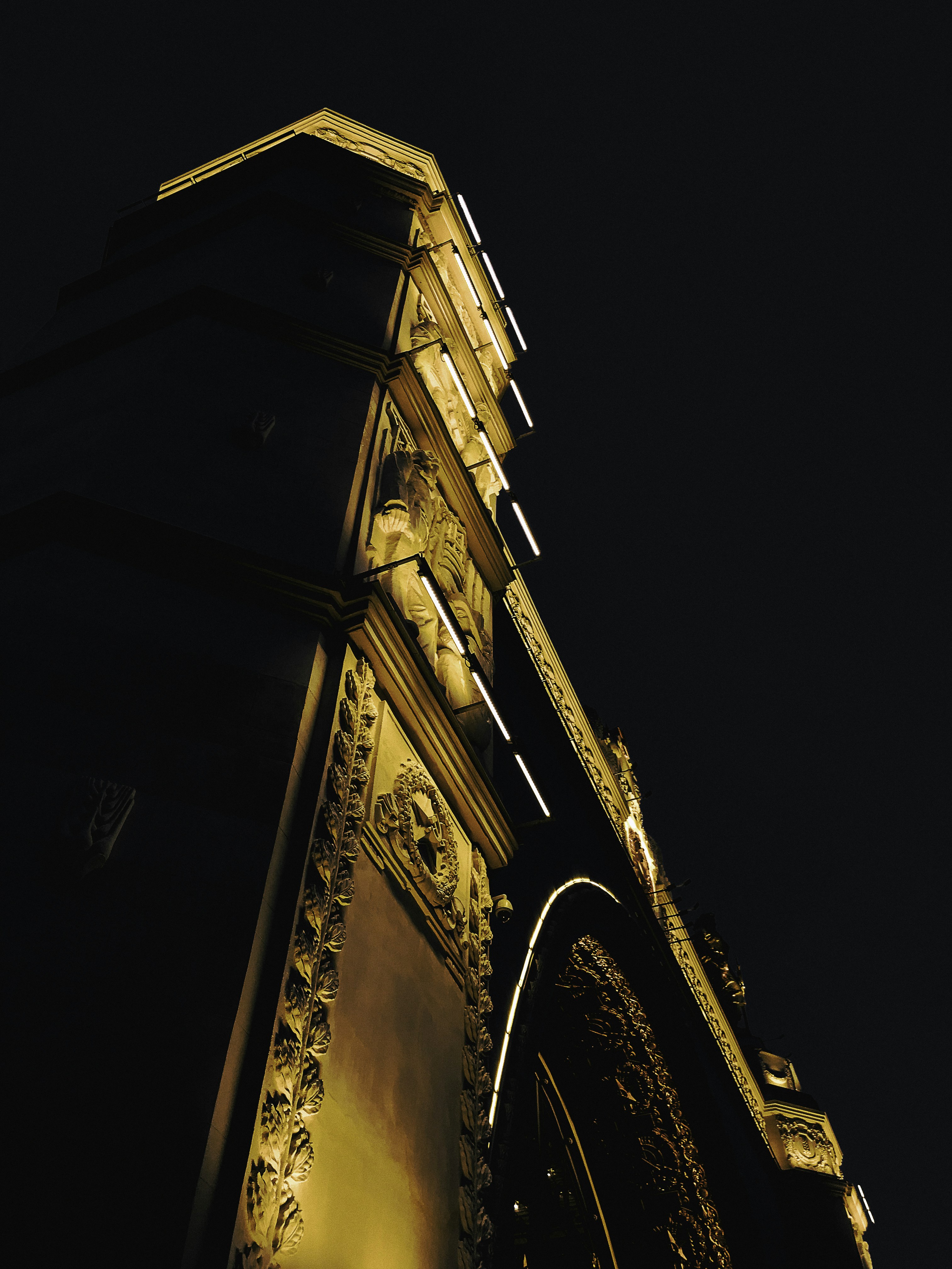 A majestic structure illuminated by warm lights, showcasing intricate details against a dark sky. The angle emphasizes its height and grandeur.