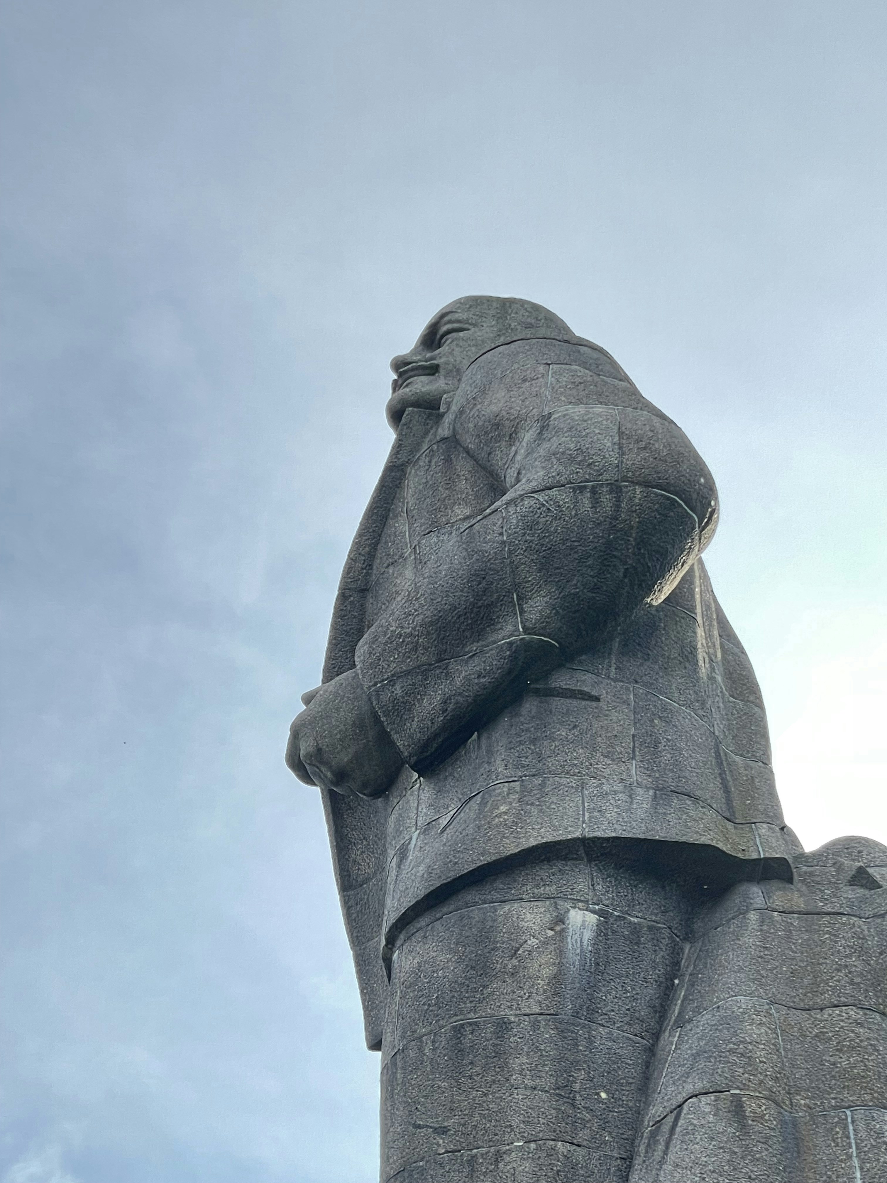 A towering statue of a historical figure, captured from a low angle against a clear sky, emphasizing its grandeur and presence.