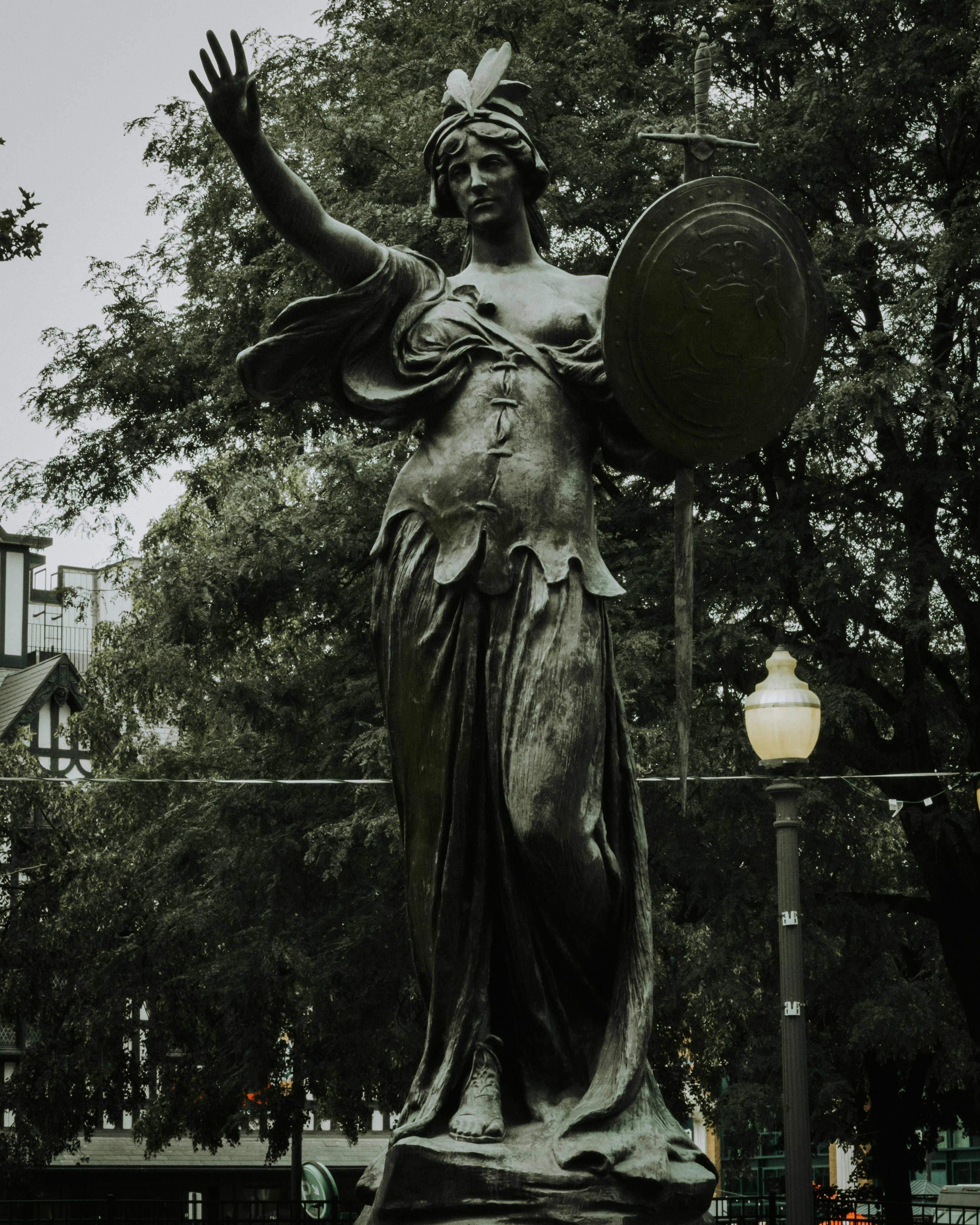 Bronze Sentinel: A draped goddess with shield in the park