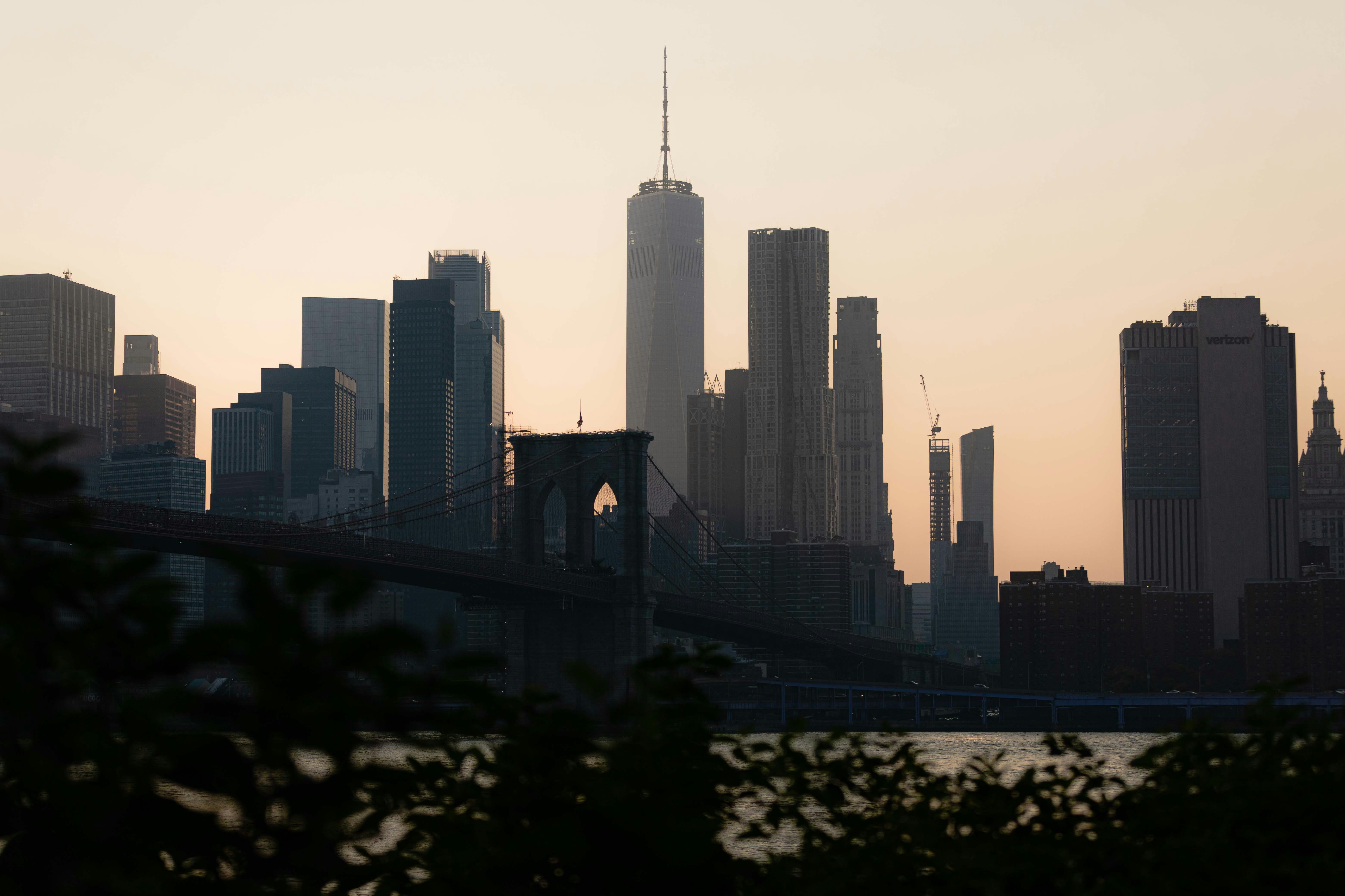 City skyline silhouettes against a soft, glowing sky at dusk.