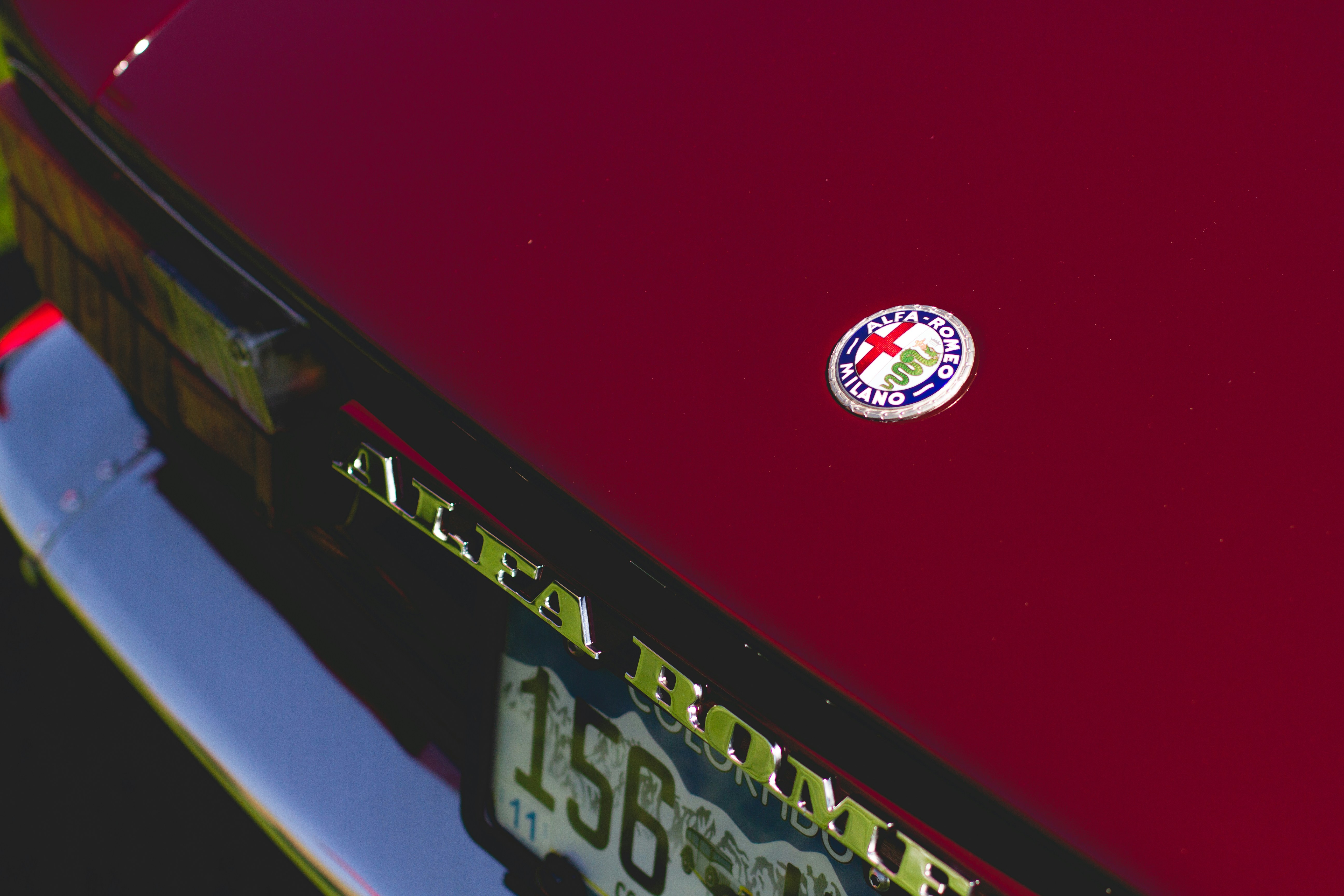 Close-up of an Alfa Romeo badge on a vintage car, highlighting its classic design and glossy finish.