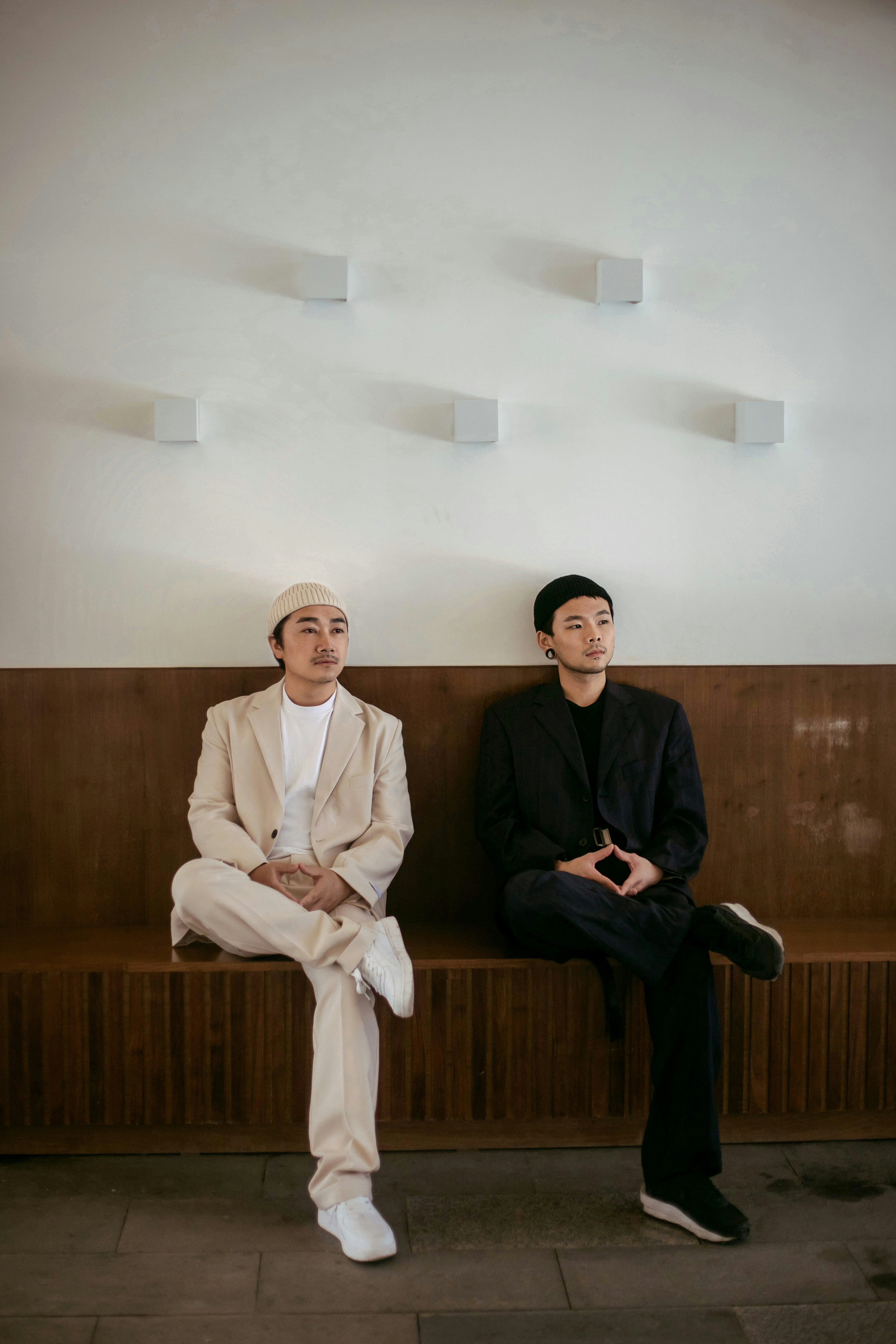 Muted Contrast: Beige and Onyx Suits Seated on a Wooden Bench