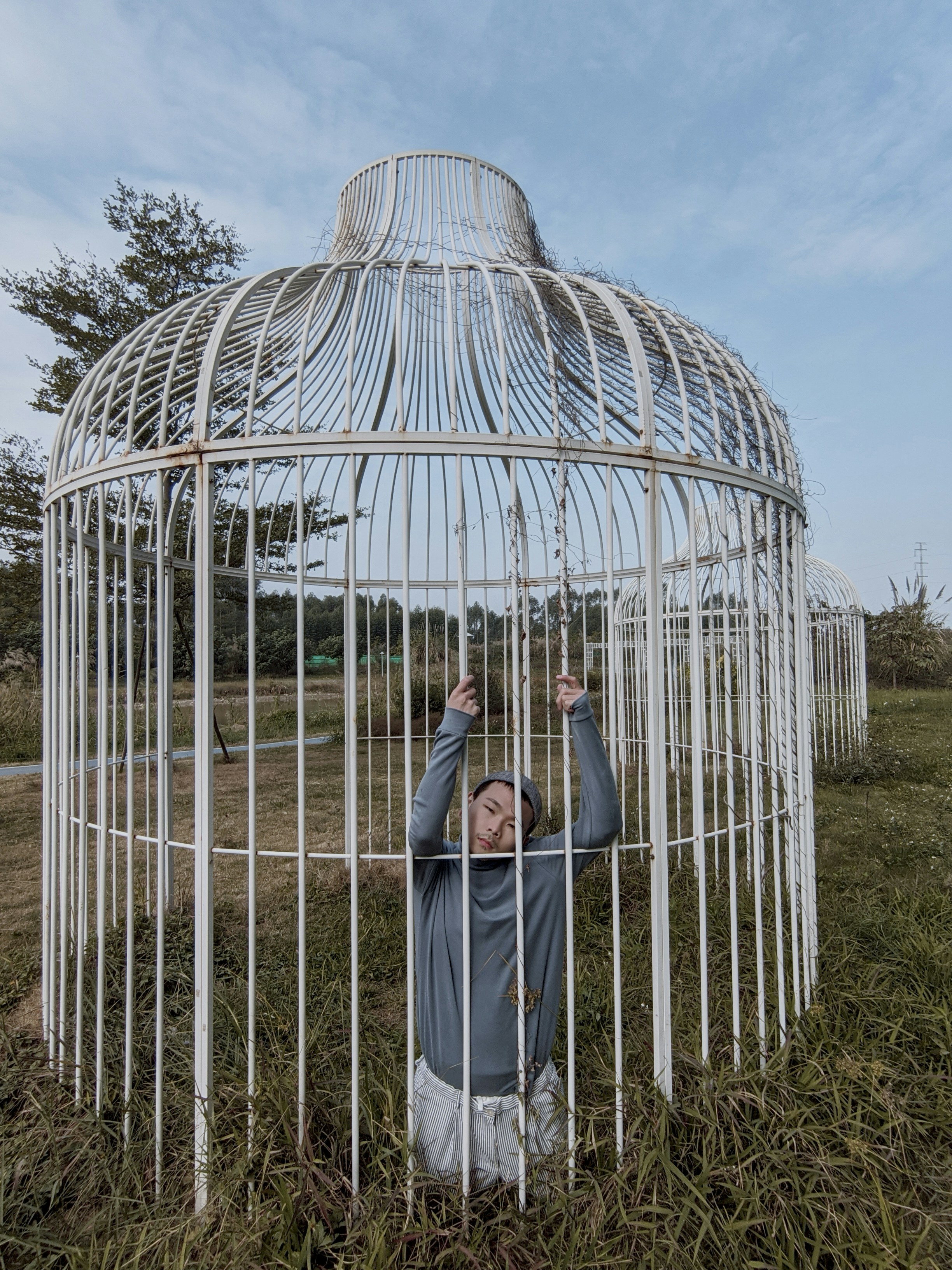 Woman in black jacket standing in front of white metal cage photo ...