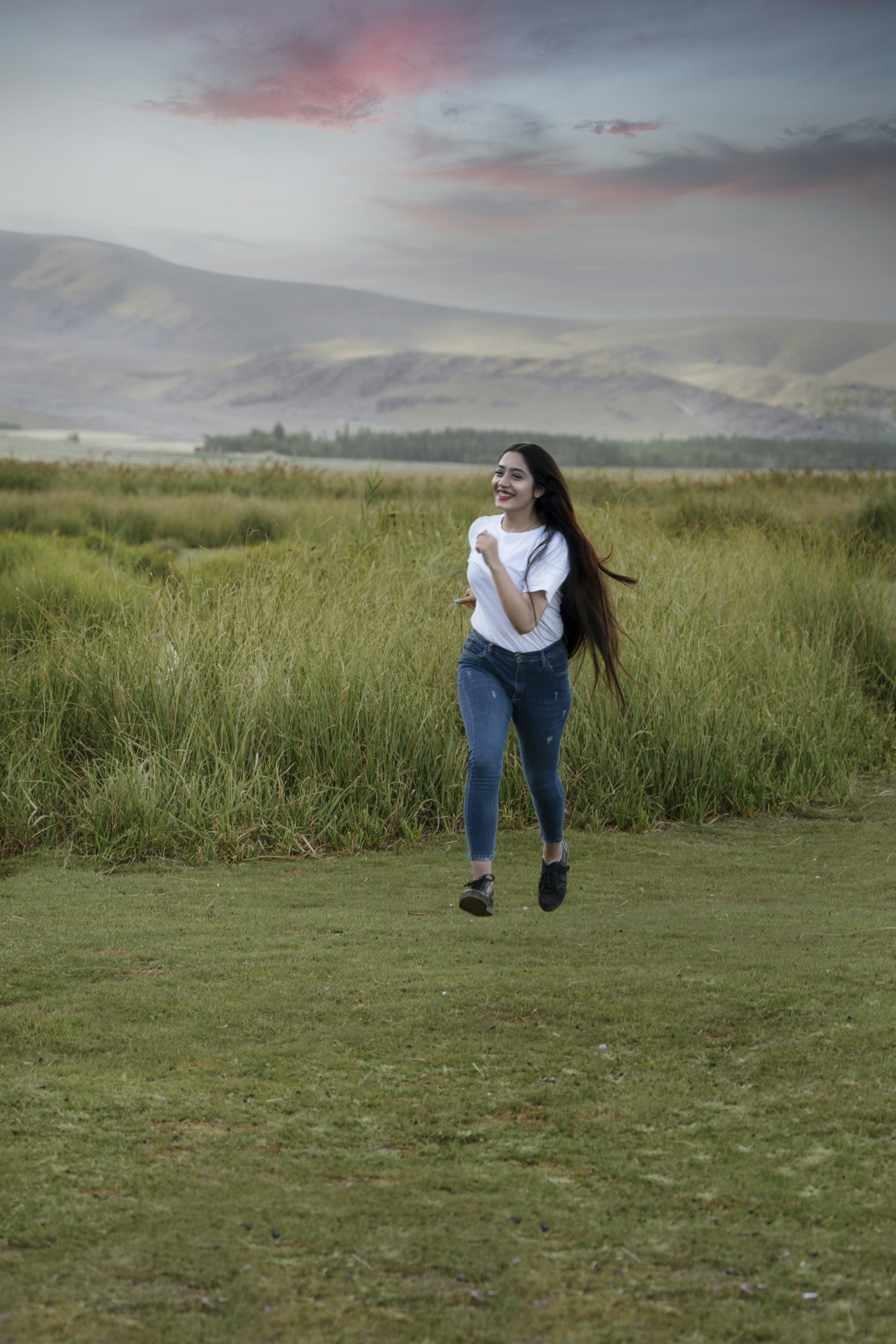 woman in white long sleeve shirt and blue denim jeans standing on green grass field during