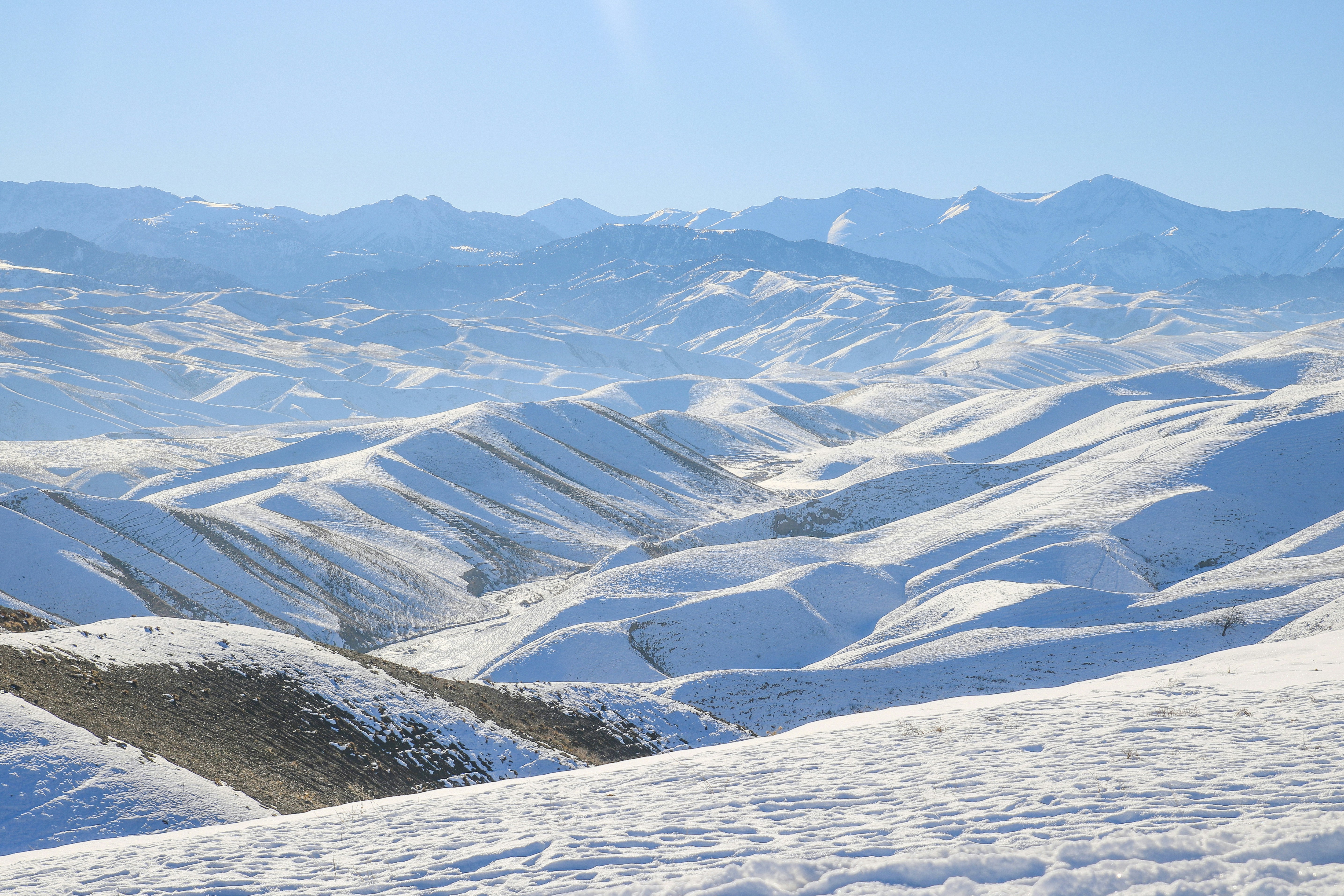 Snow-draped hills stretch into the distance under a clear blue sky.