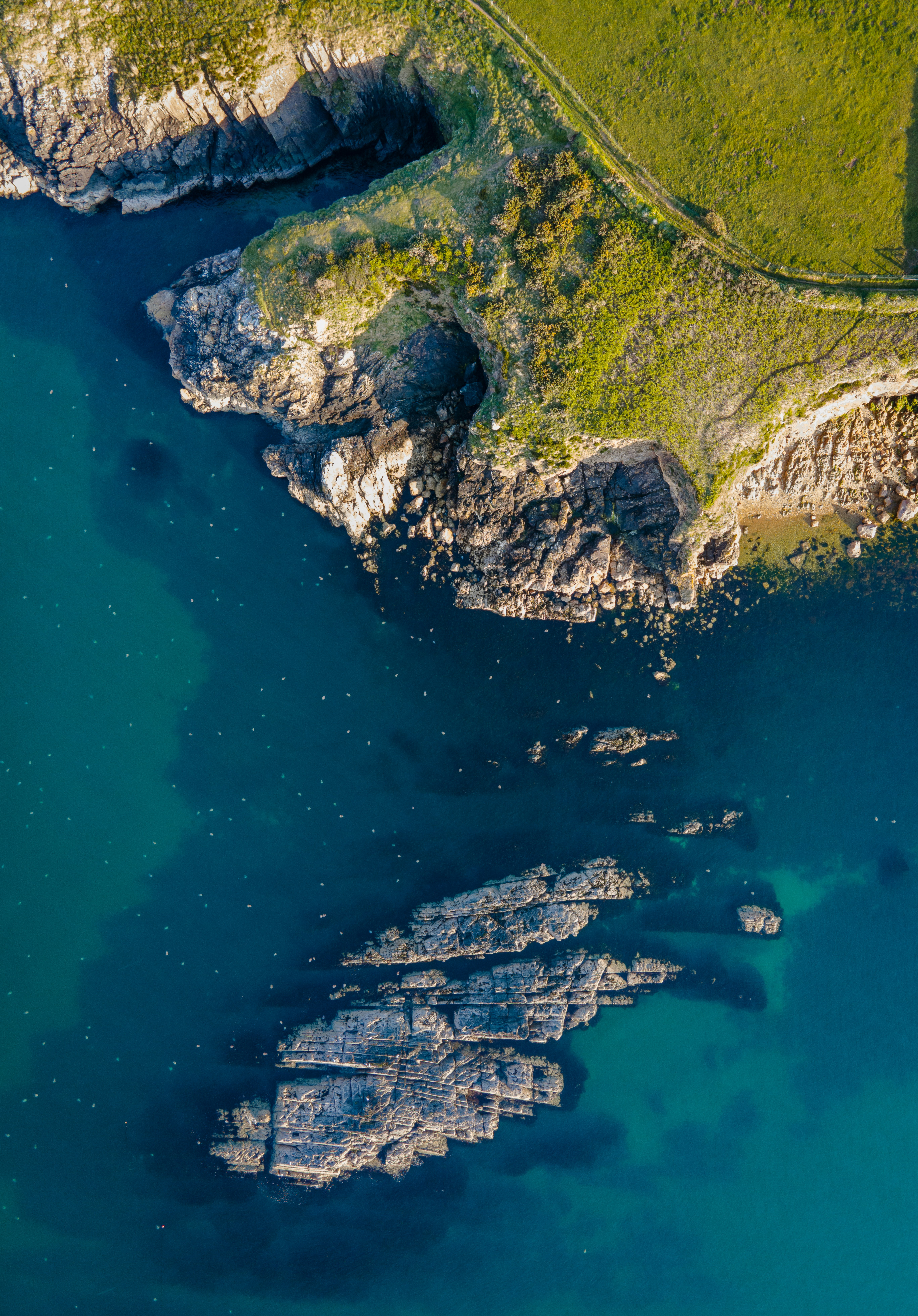 Aerial view of green and brown rock formation beside body of water ...