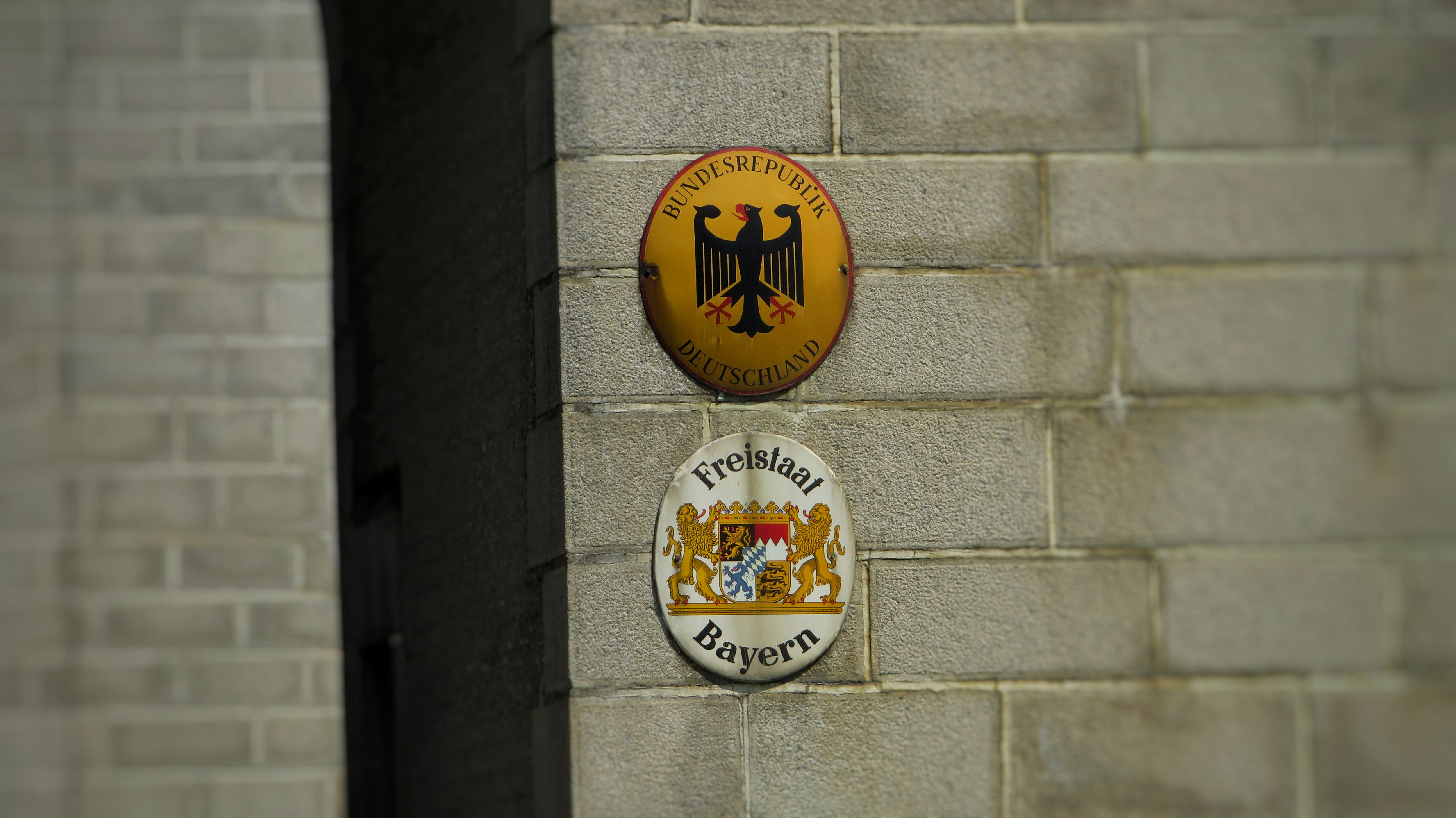 Two distinct emblems displayed on a textured wall, representing German and Bavarian heritage.