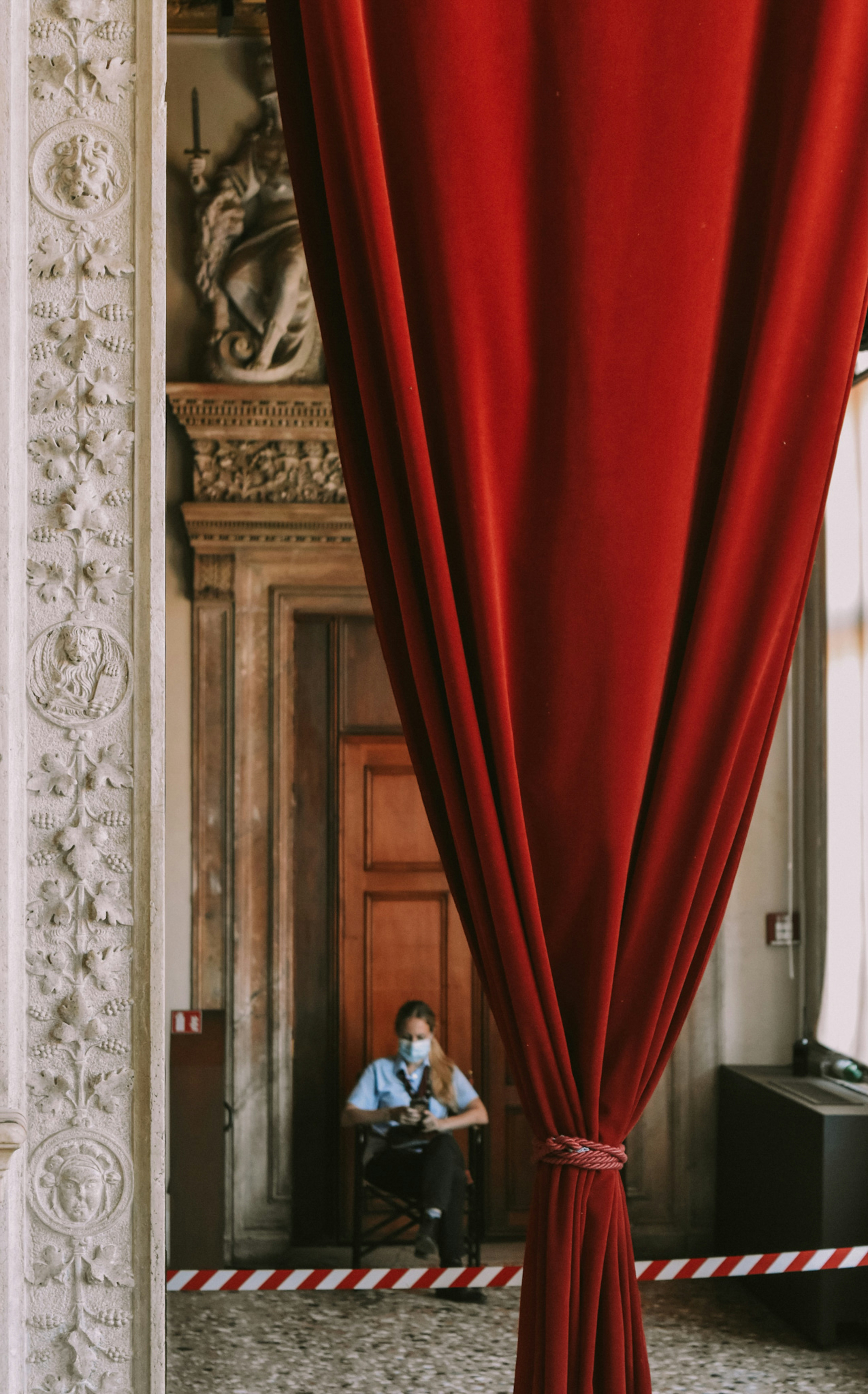 Red Curtain, Quiet Moment: A Masked Visitor in a Historic Hall