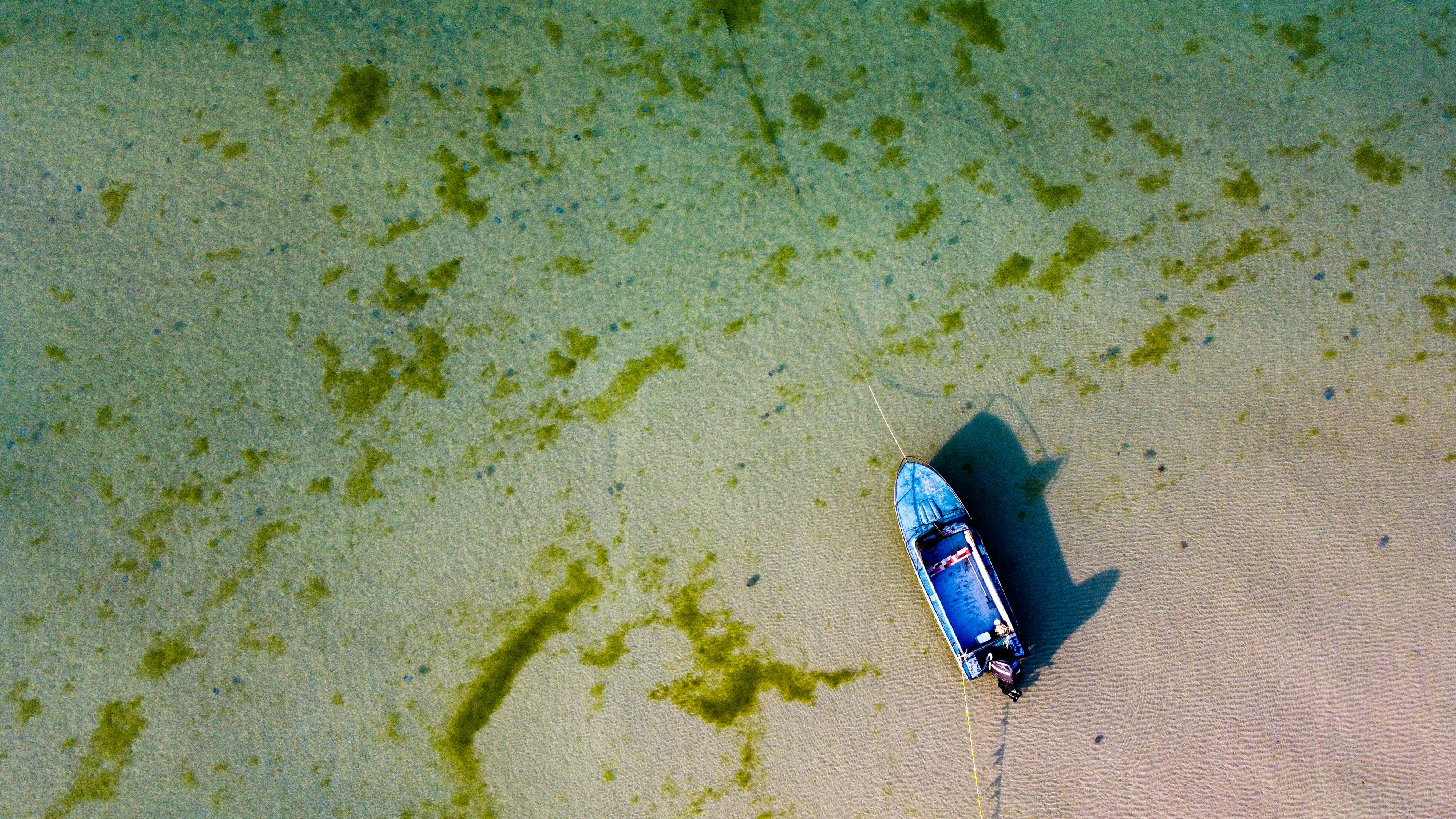 Drifting Serenity: A Lone Vessel in Shallow Waters