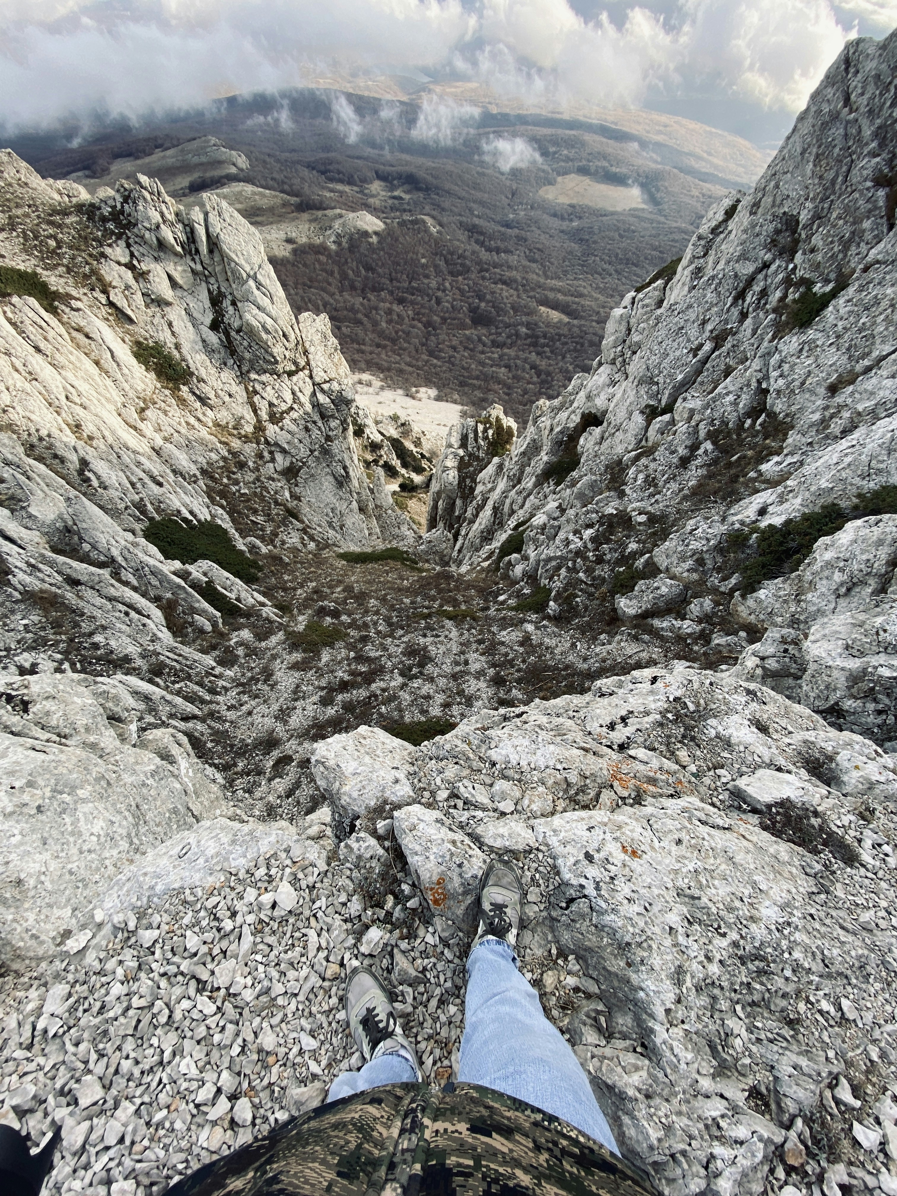 person in blue denim jeans sitting on rocky mountain during daytime