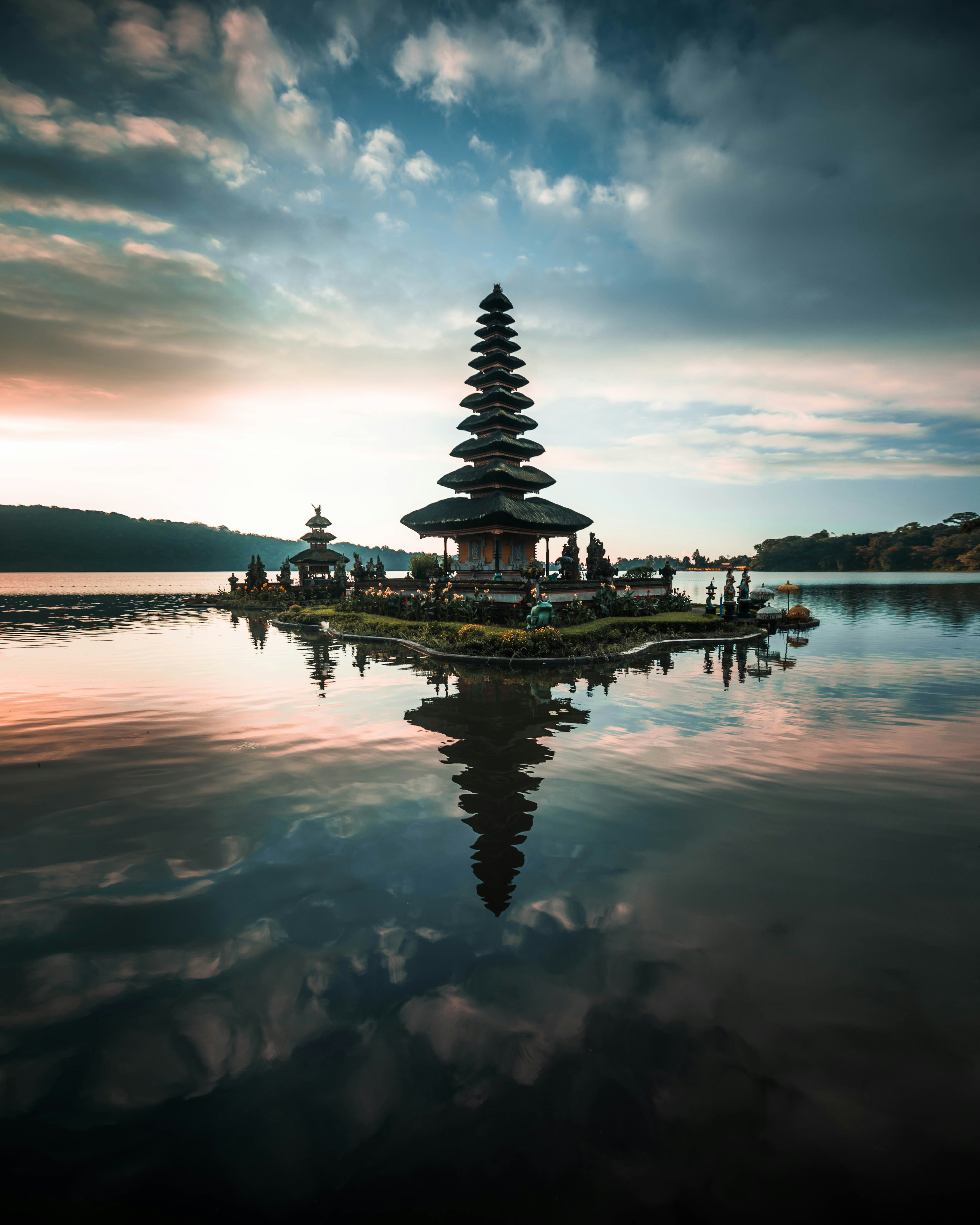 Traditional Balinese temple situated on a tranquil lake, surrounded by lush greenery and reflecting in the water's surface.
