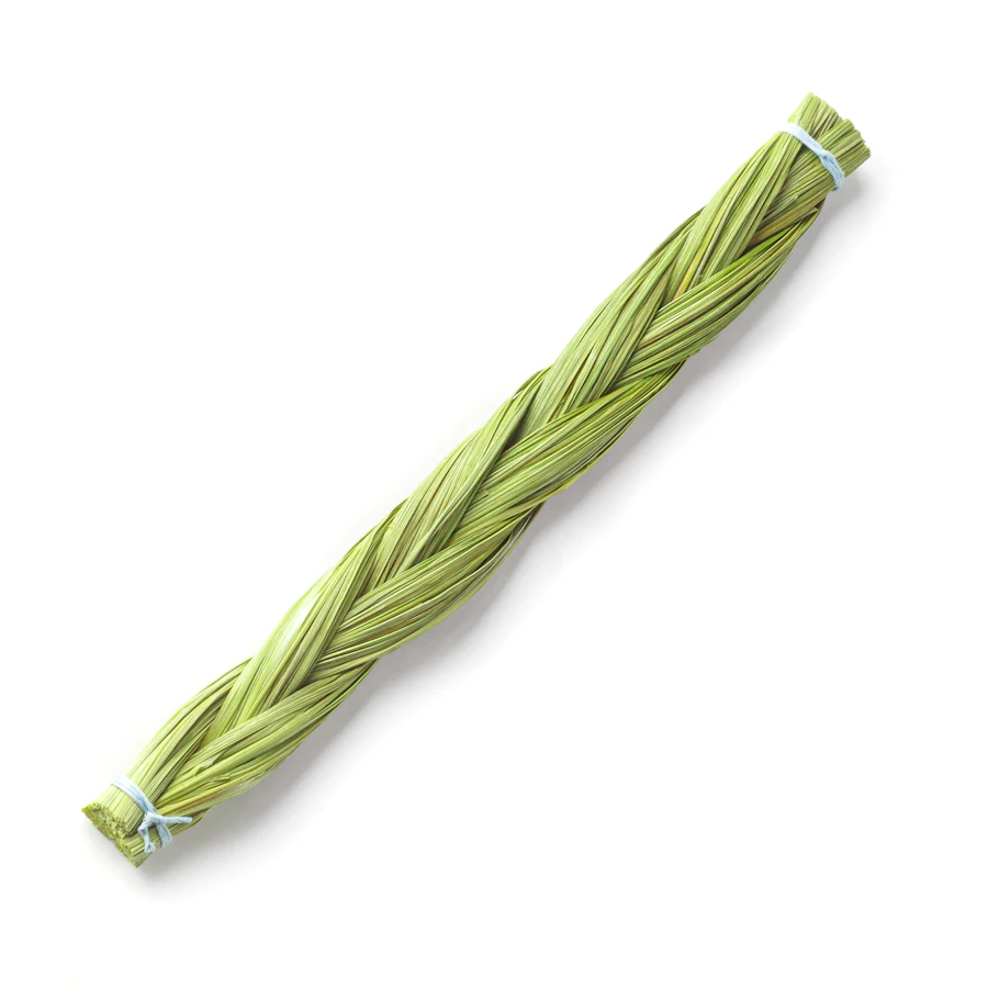 A long braided bundle of green palm leaves tied at both ends, resting diagonally on a white background.